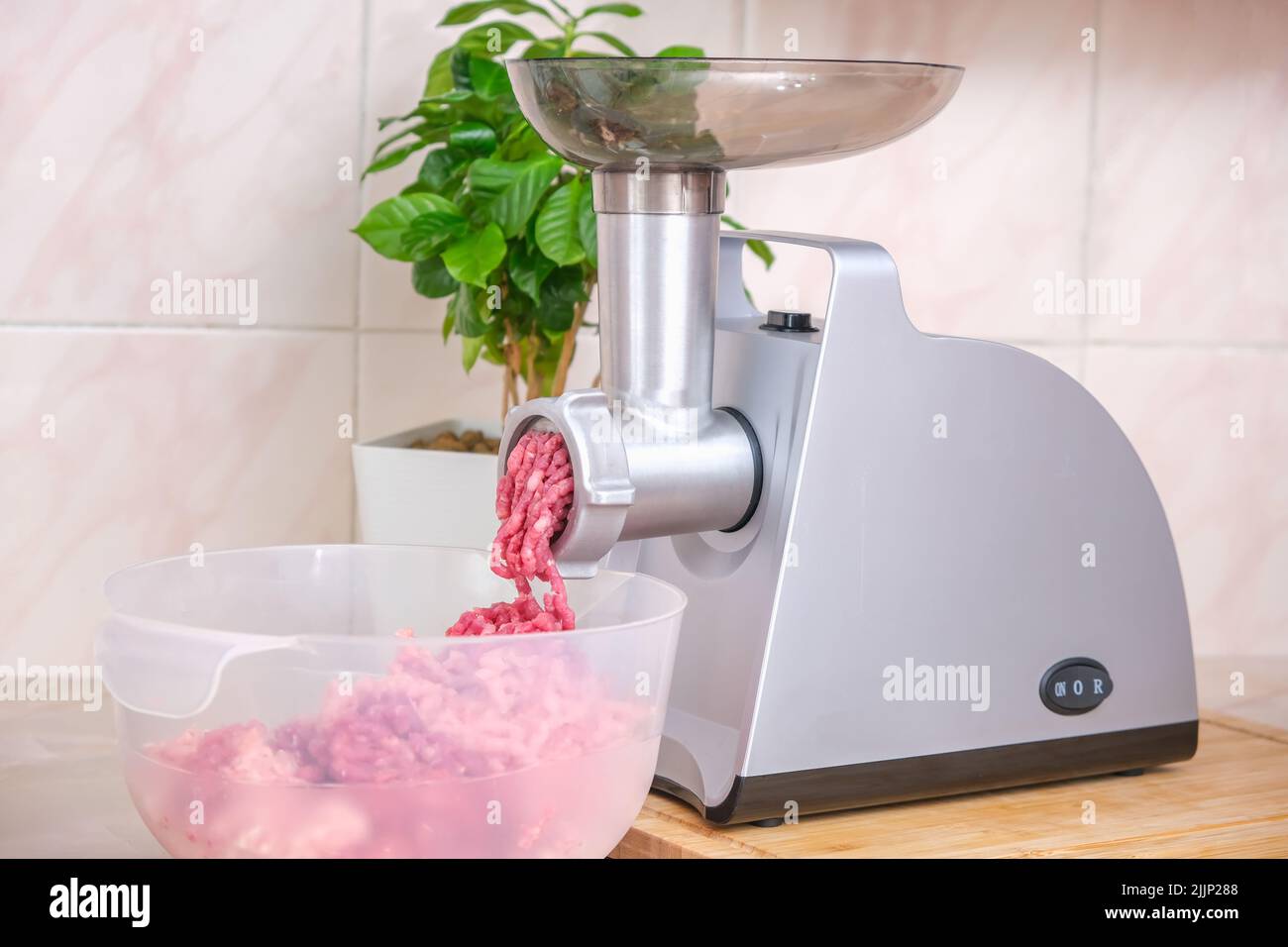 A man processes meat in an electric meat grinder. Preparation of minced ...