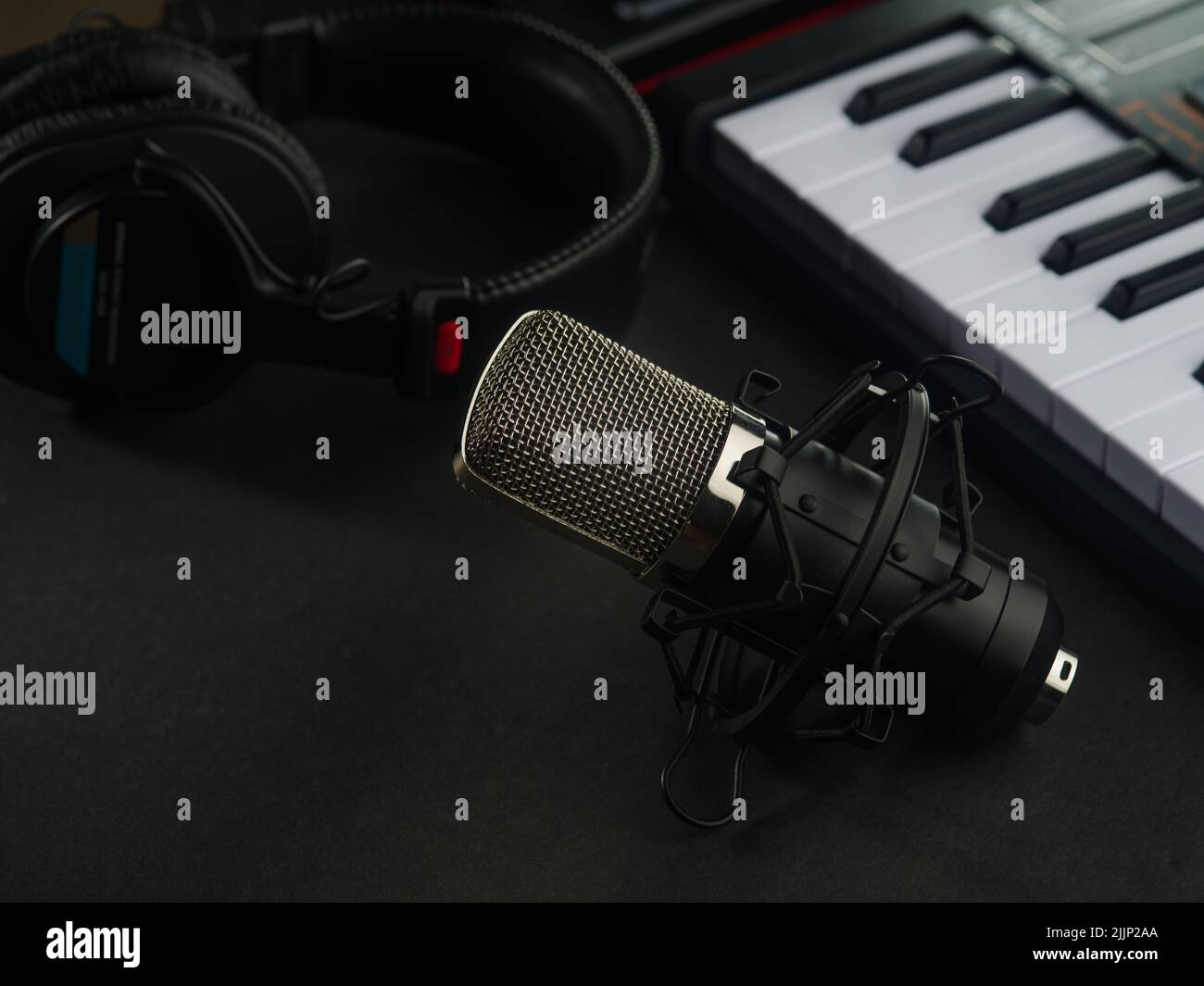 A studio microphone, studio headphones and a modern synthesizer-midi ...