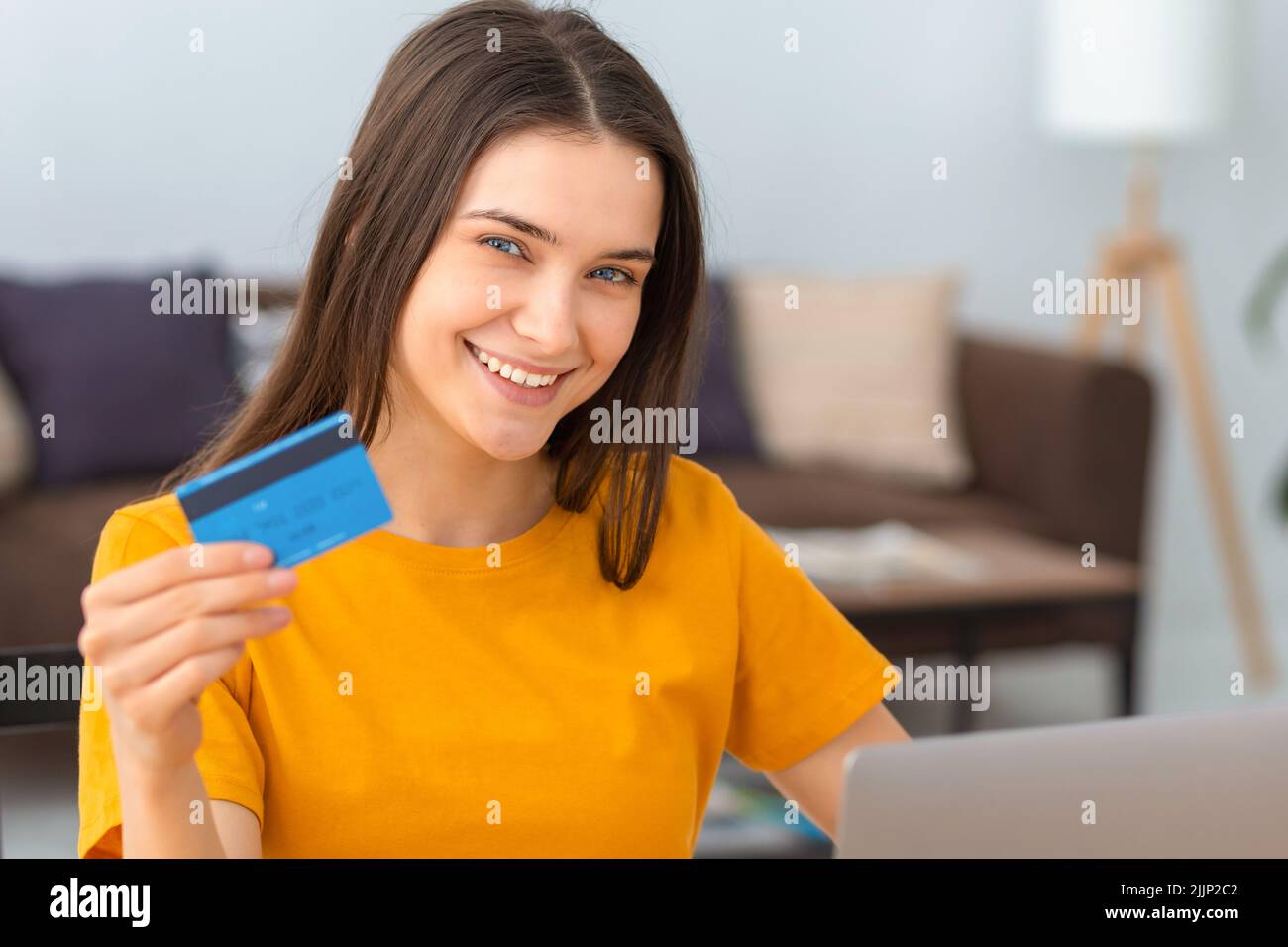 Young woman hold bank credit card, shopping online using laptop, buying ...