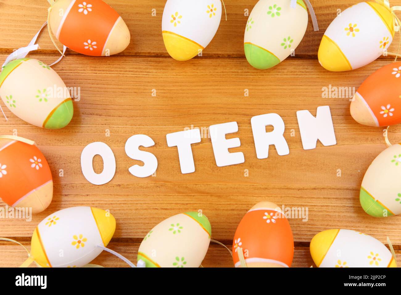 A sign with Happy Easter writing on it next to painted eggs on a wooden ...