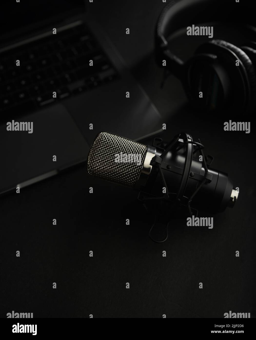 Studio microphone, studio headphones on a laptop on a black background ...