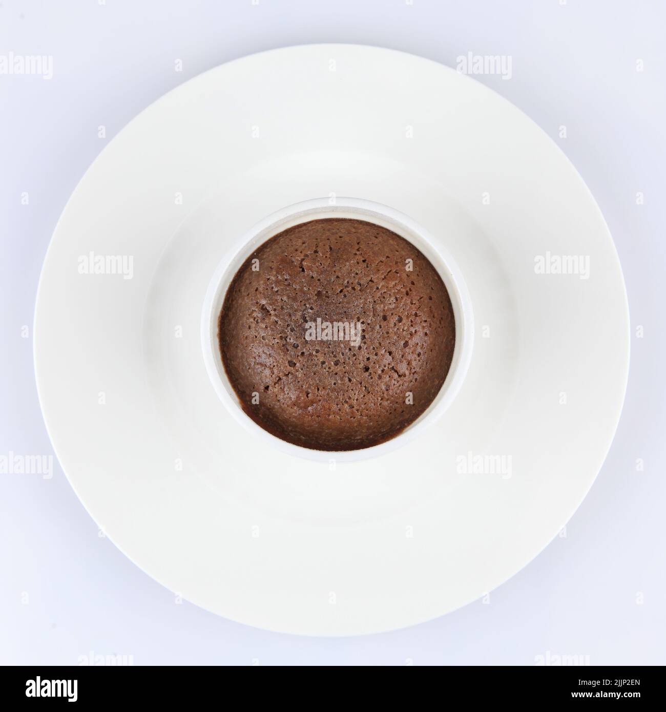 A top view of chocolate souffle in a classic white porcelain ramekin on ...