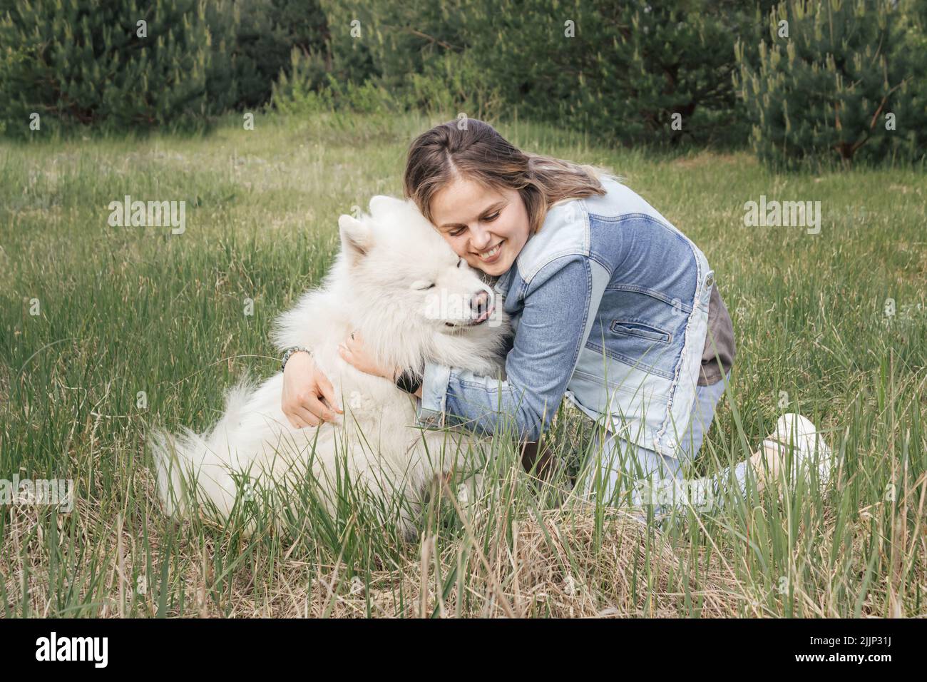 Young beautiful woman hugging her dog samoyed after walking in the park ...