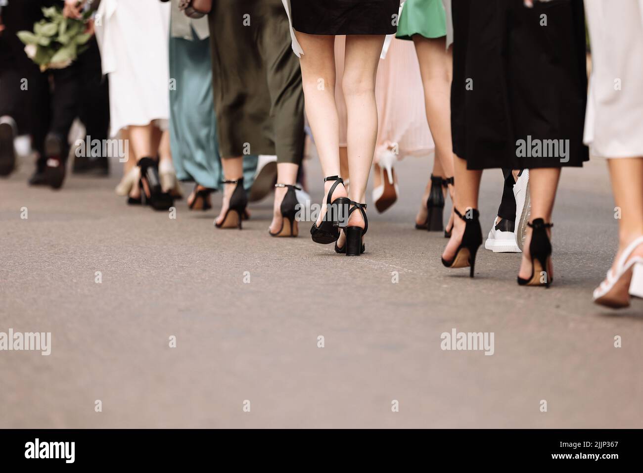 the feet of the group of people are walking outdoors. graduation day ...