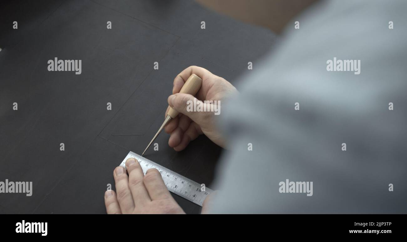 Close up of leather craftsman working with natural leather by awl and ...
