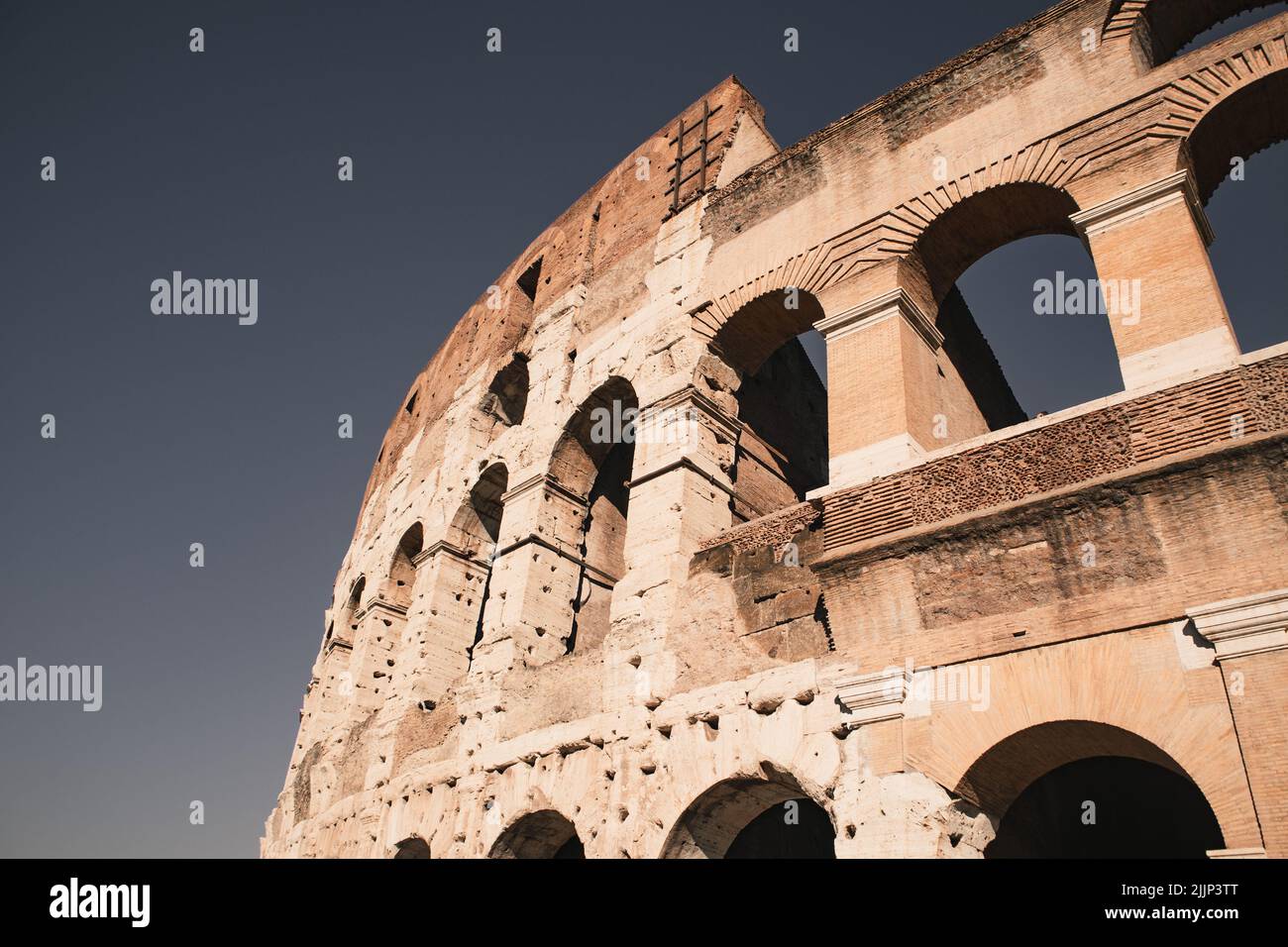 A low angle shot of the Colosseum on the blue sky background, Rome ...