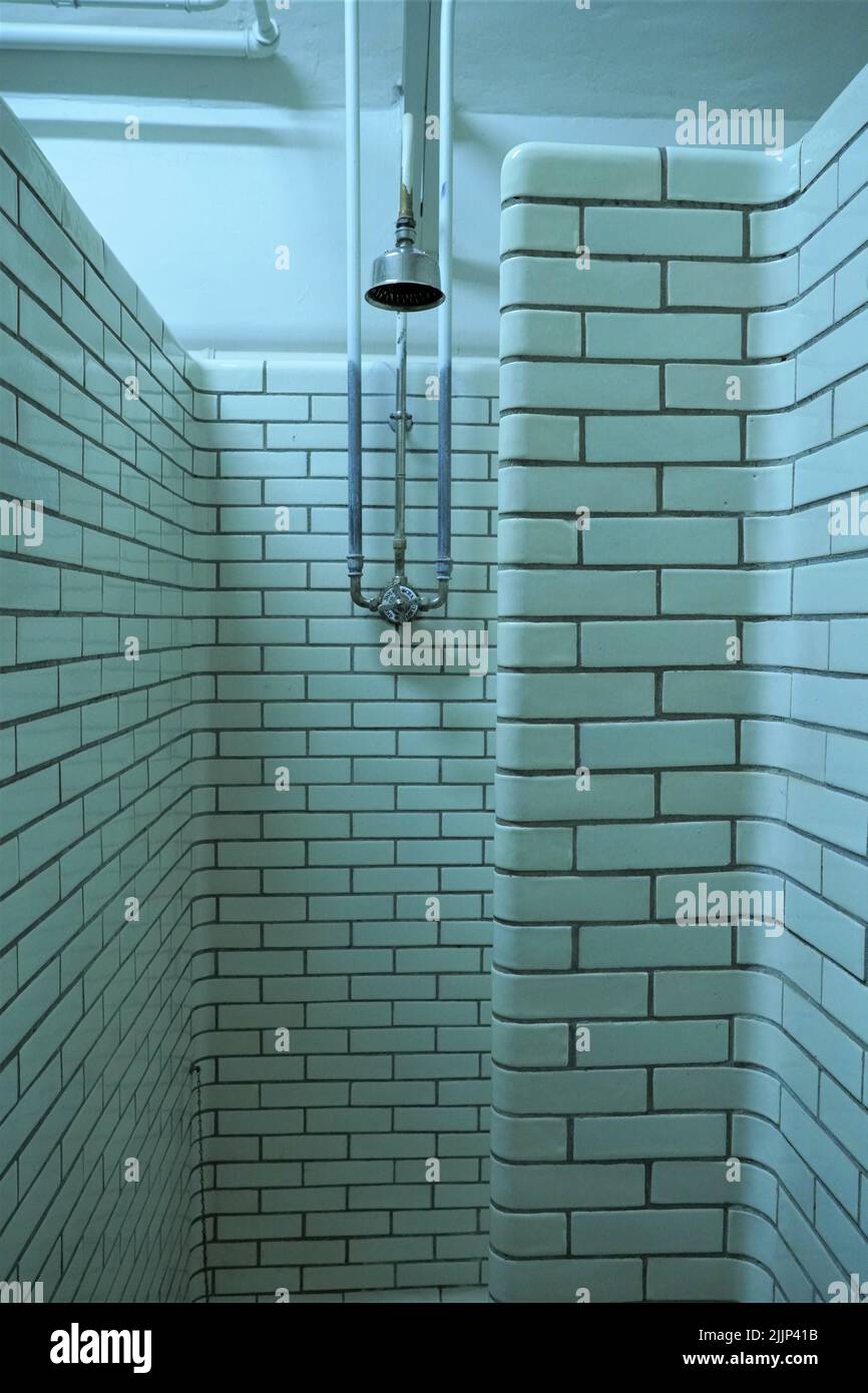 A vertical shot of the interior of an old shower with tiles on the ...
