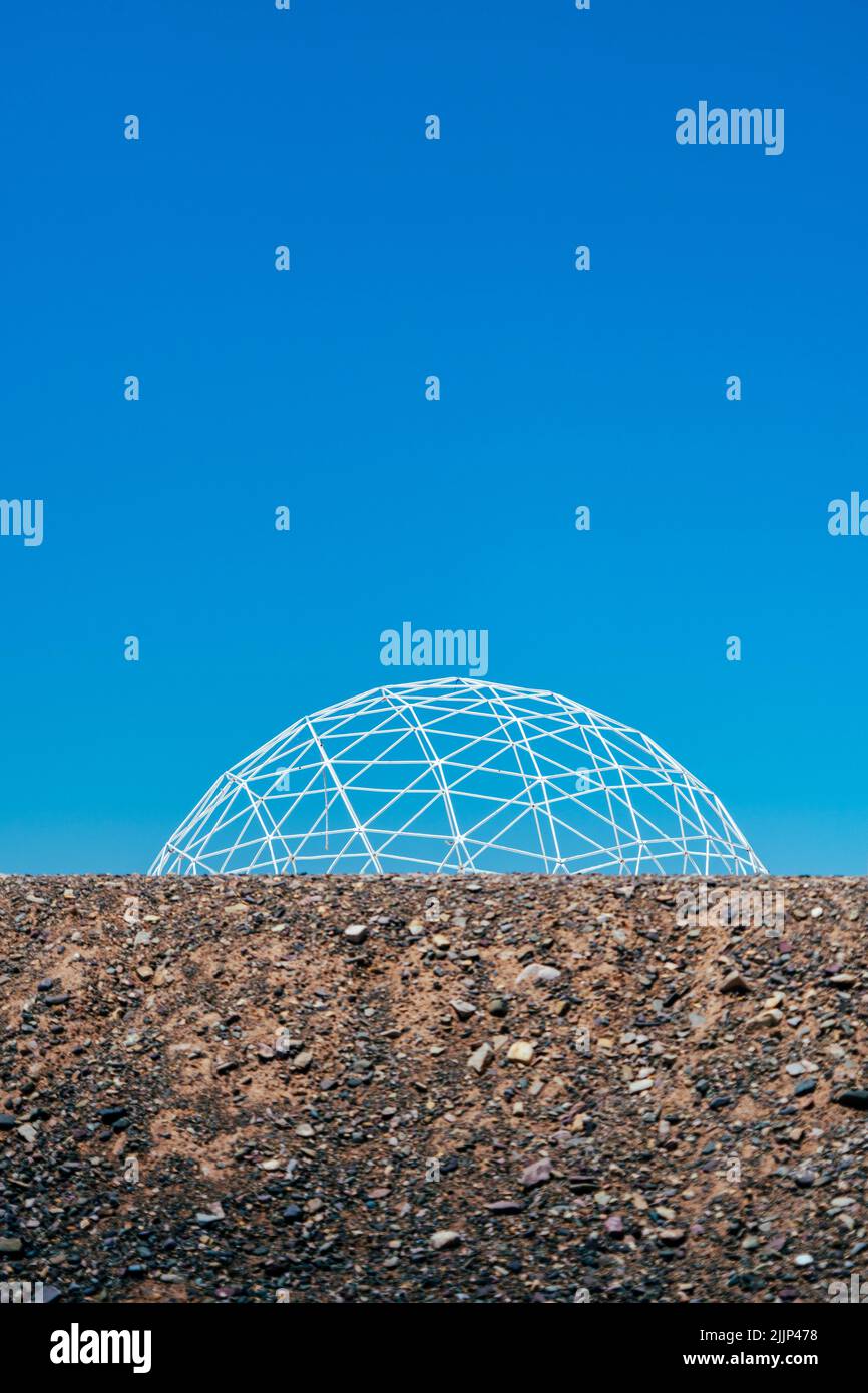 A closeup of a Geodesic dome behind a hill with a blue sky background ...