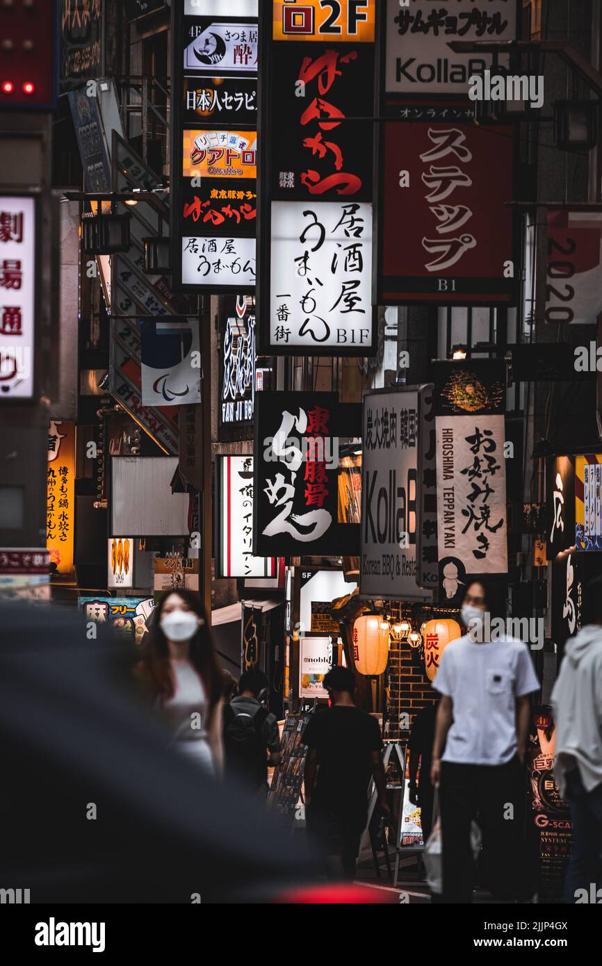 A vertical shot of a street in Tokyo with advertisements and people ...