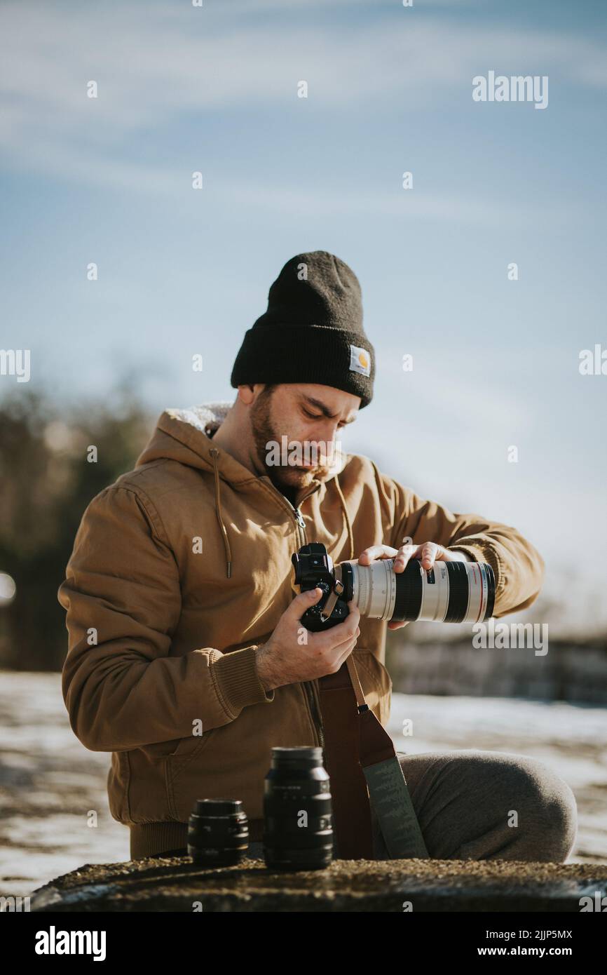 A vertical shot of a young photographer using the camera at the snowy ...