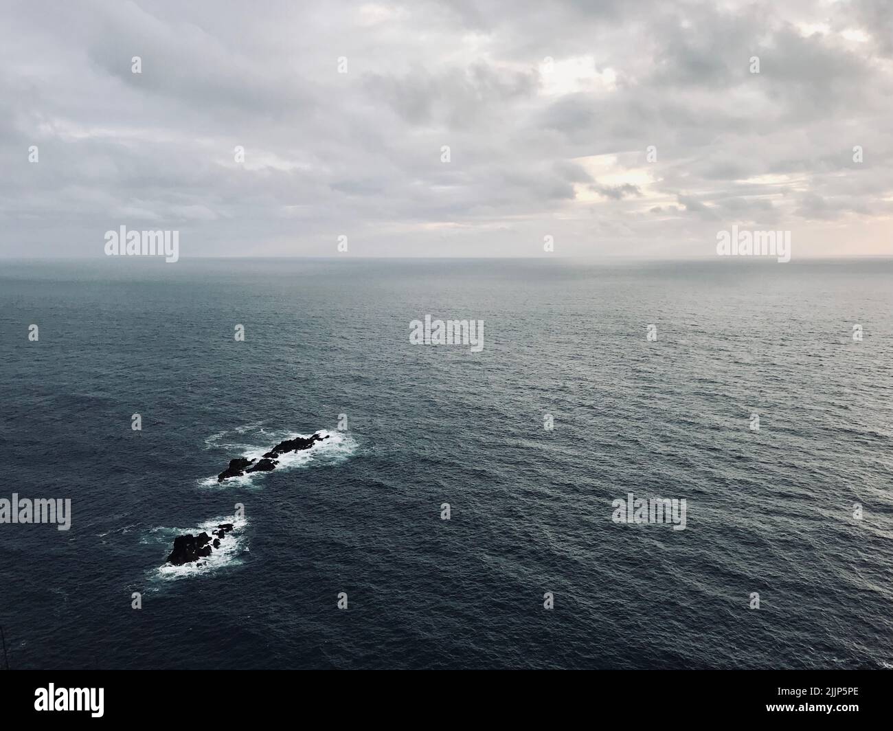 An aerial view of the tranquil ocean under the cloudy sky at the gloomy ...