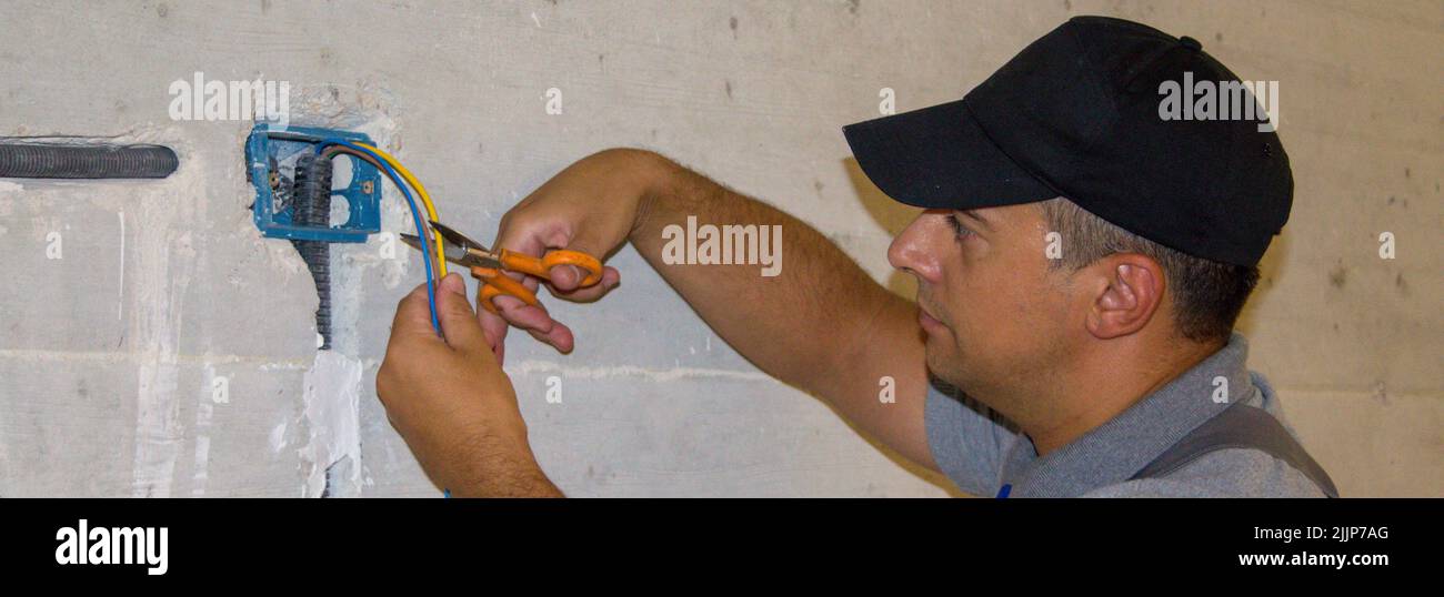Image of a handyman electrician cutting power cables with a pair of ...