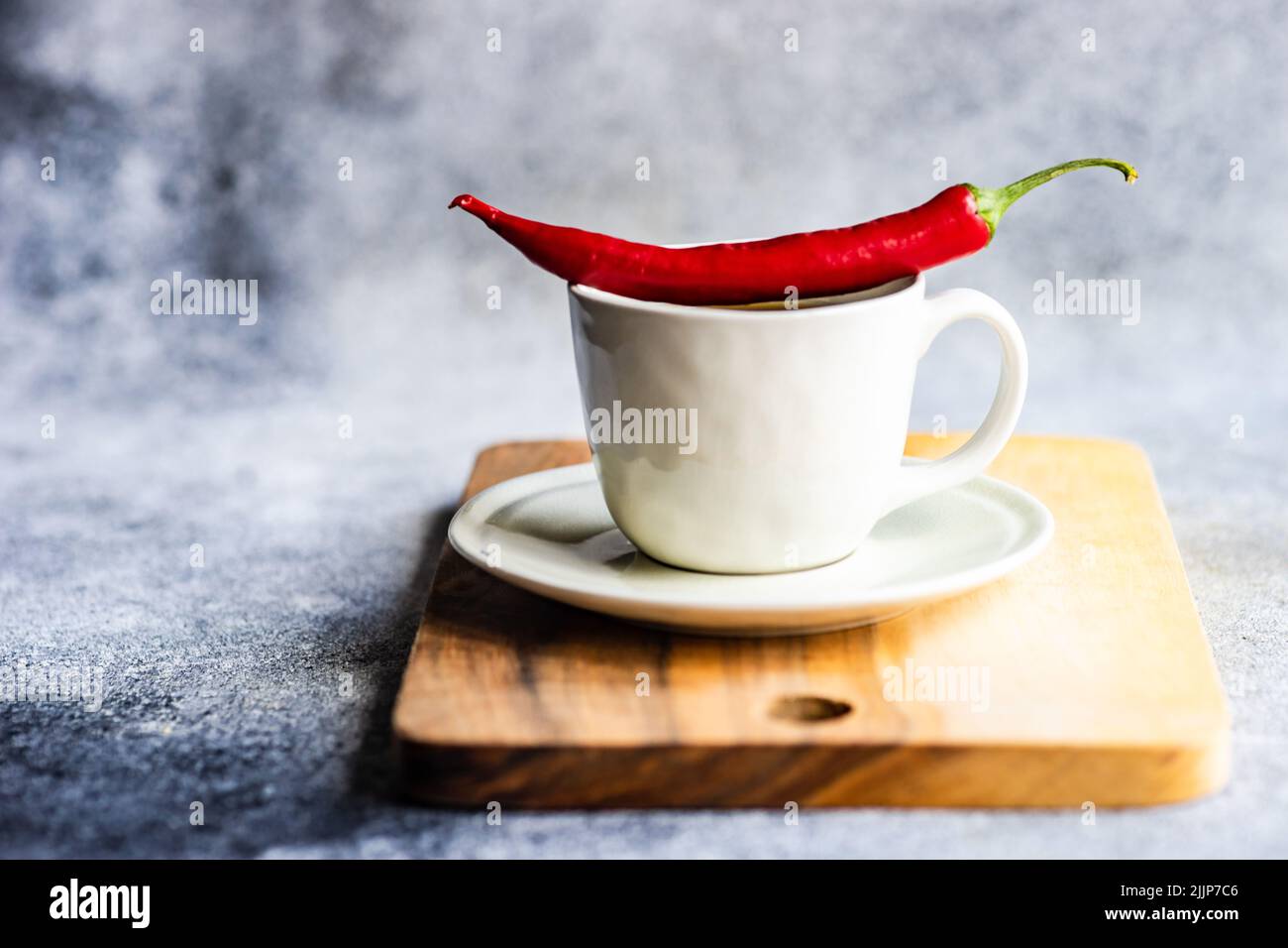 Cup of coffee with a red chilli pepper on a chopping board Stock Photo ...