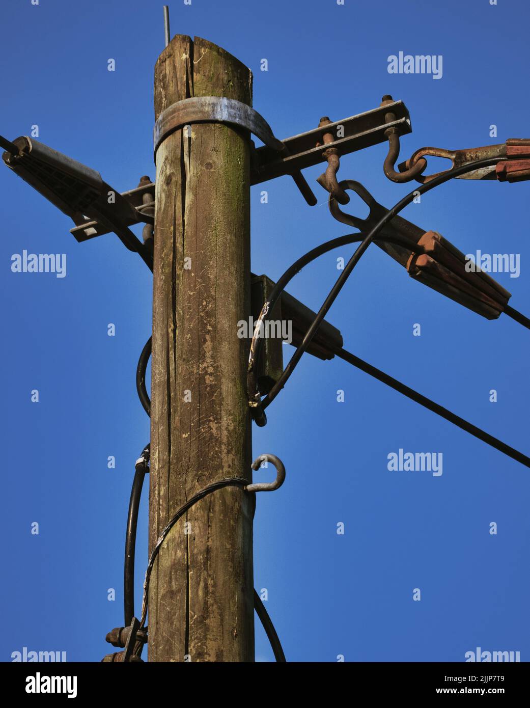A low angle vertical closeup of a wooden electricity pole against the ...