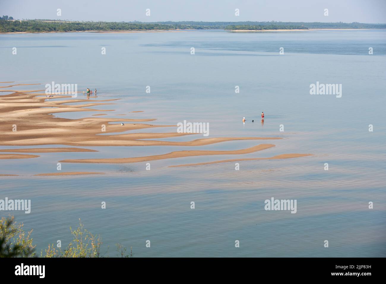 Summer landscape, distant view of people enjoying the beach of a river ...