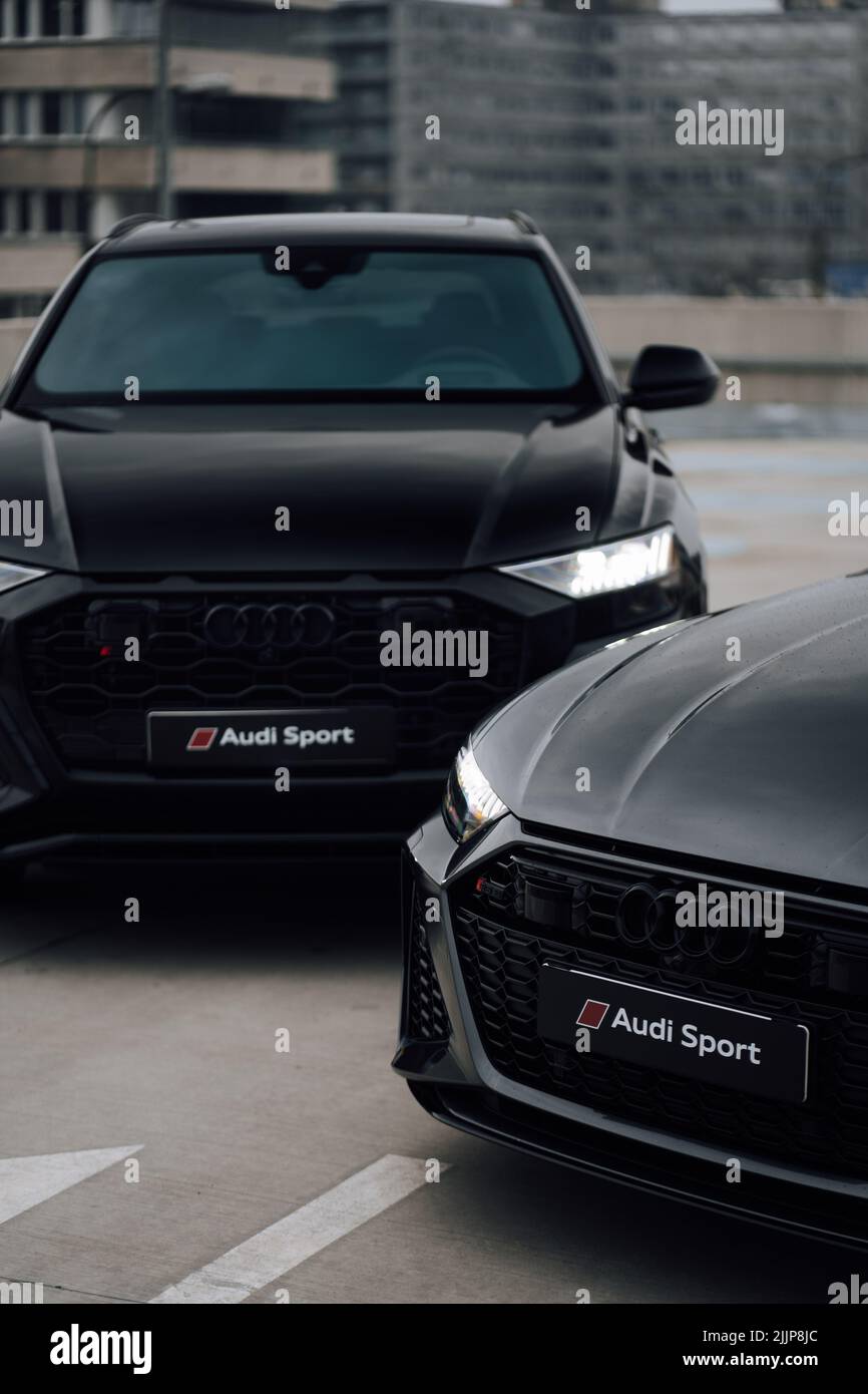 A vertical shot of a black Audi RS Q8 and silver Audi RS 6 in a parking ...