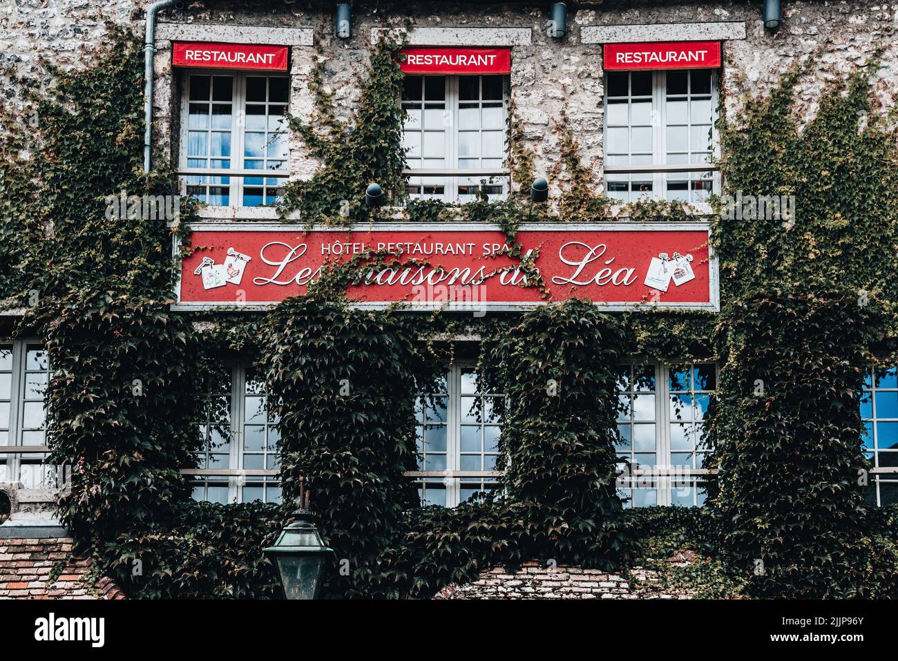 The beautiful facade with plants and a vibrant signboard of "Les ...
