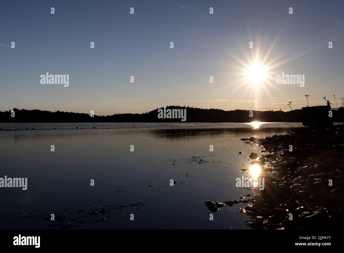 A beautiful day outdoors at a lake with the sun rays shining on it and ...