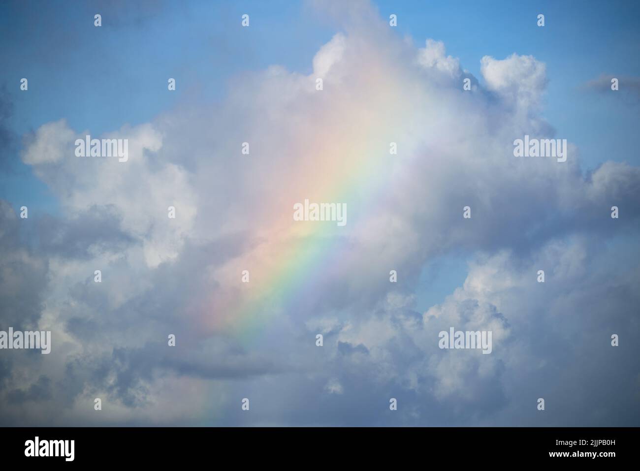 A beautiful low angle view of a light rainbow on the clouds in the sky ...