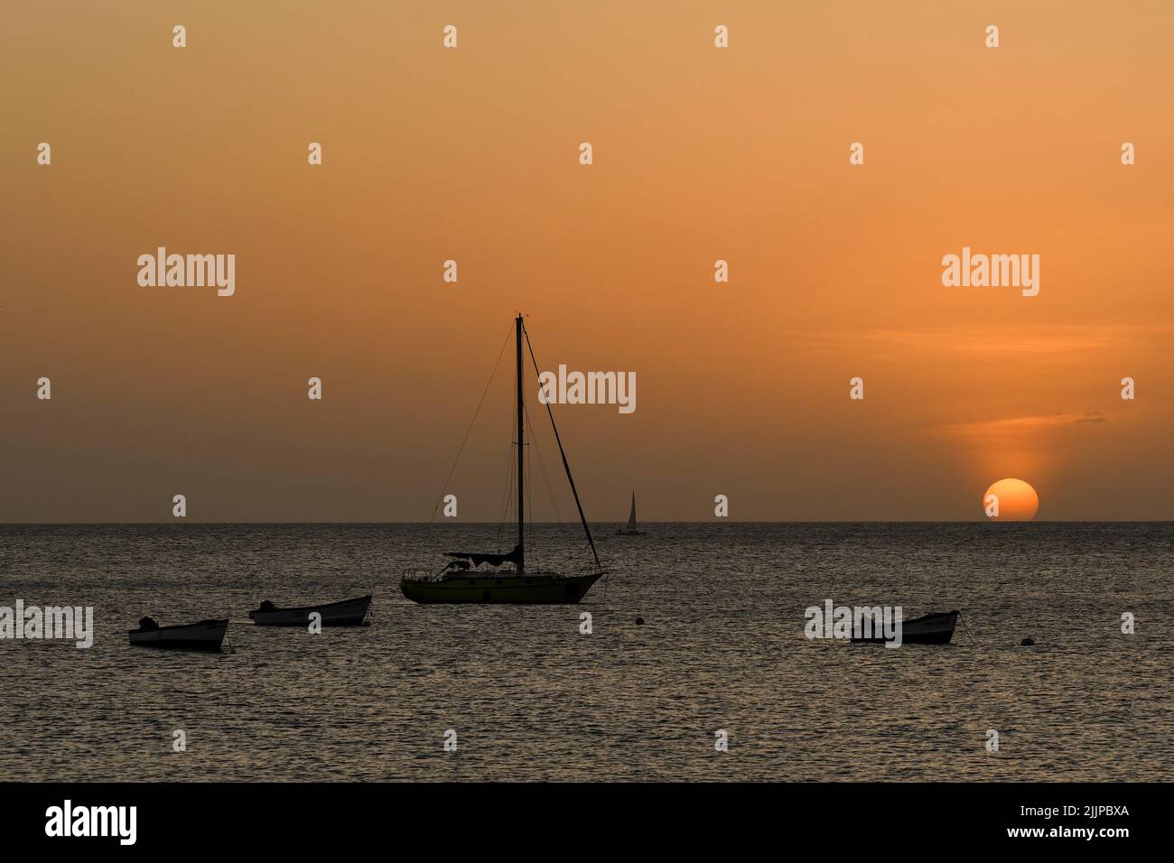 A closeup of boats in a sea with an orange cloudy sky background Stock ...