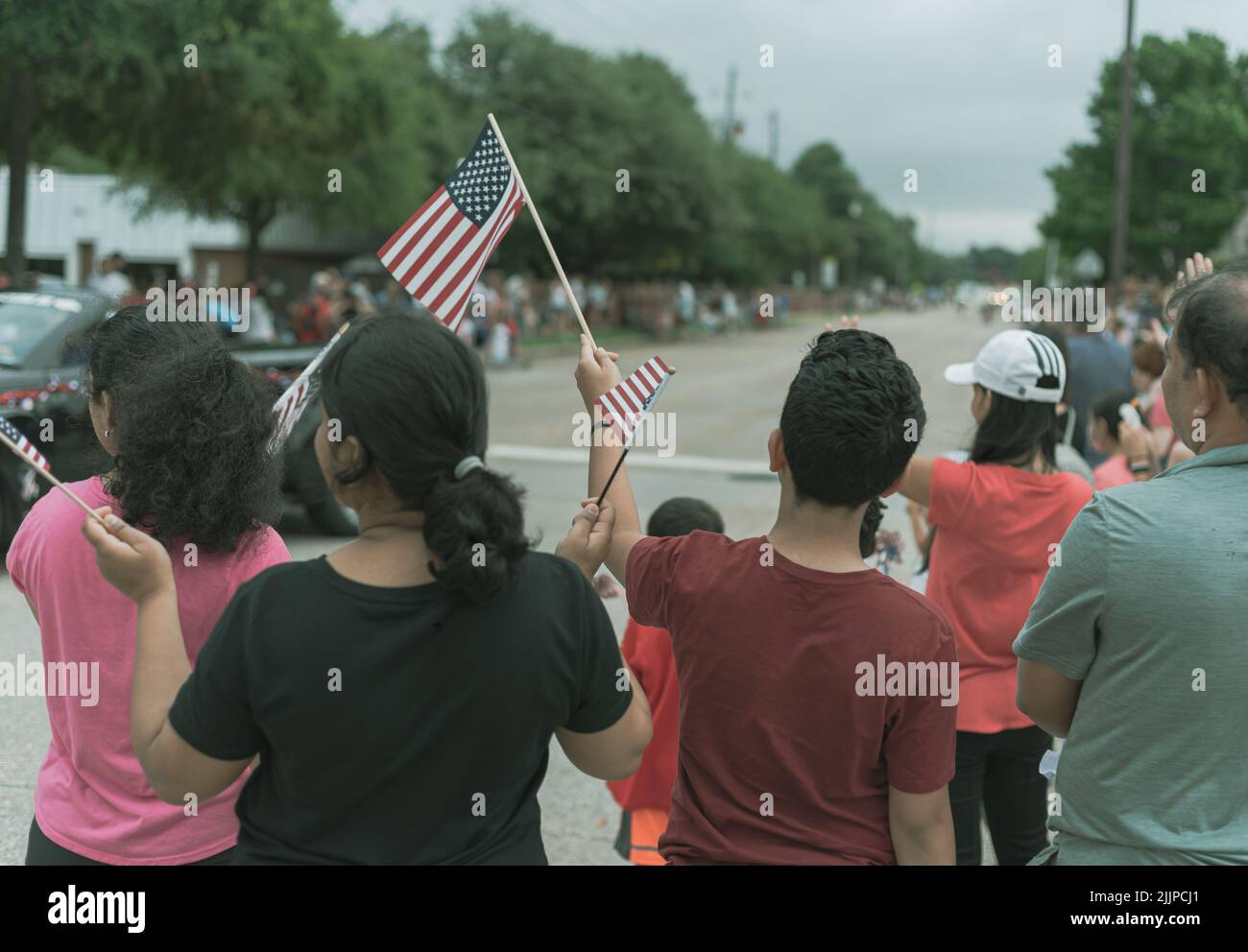 Diverse people waving American flags watching street parade on July 4th ...
