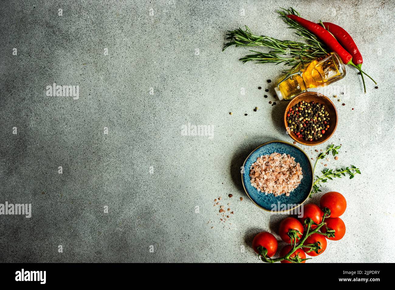 Overhead view of salt, pepper, olive oil, cherry tomatoes, rosemary and ...