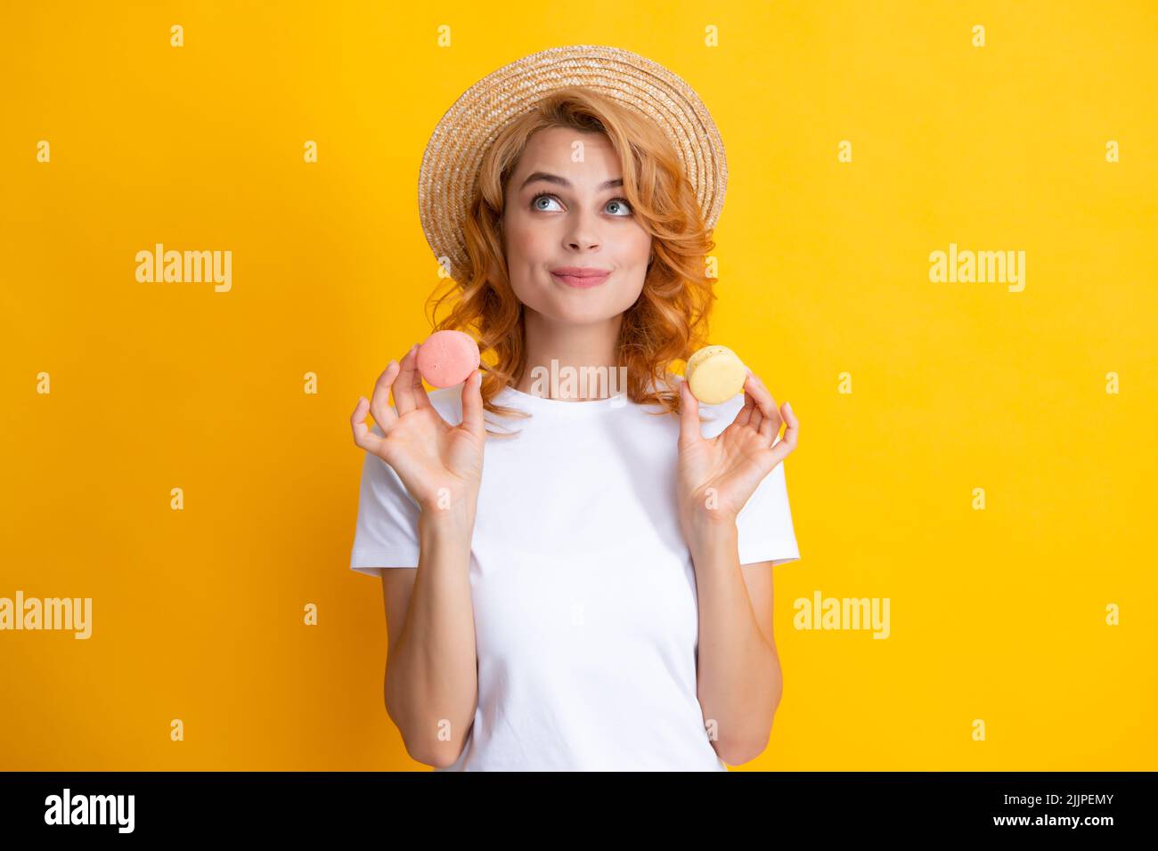 Young pleased woman isolated over yellow background eating macaroons ...