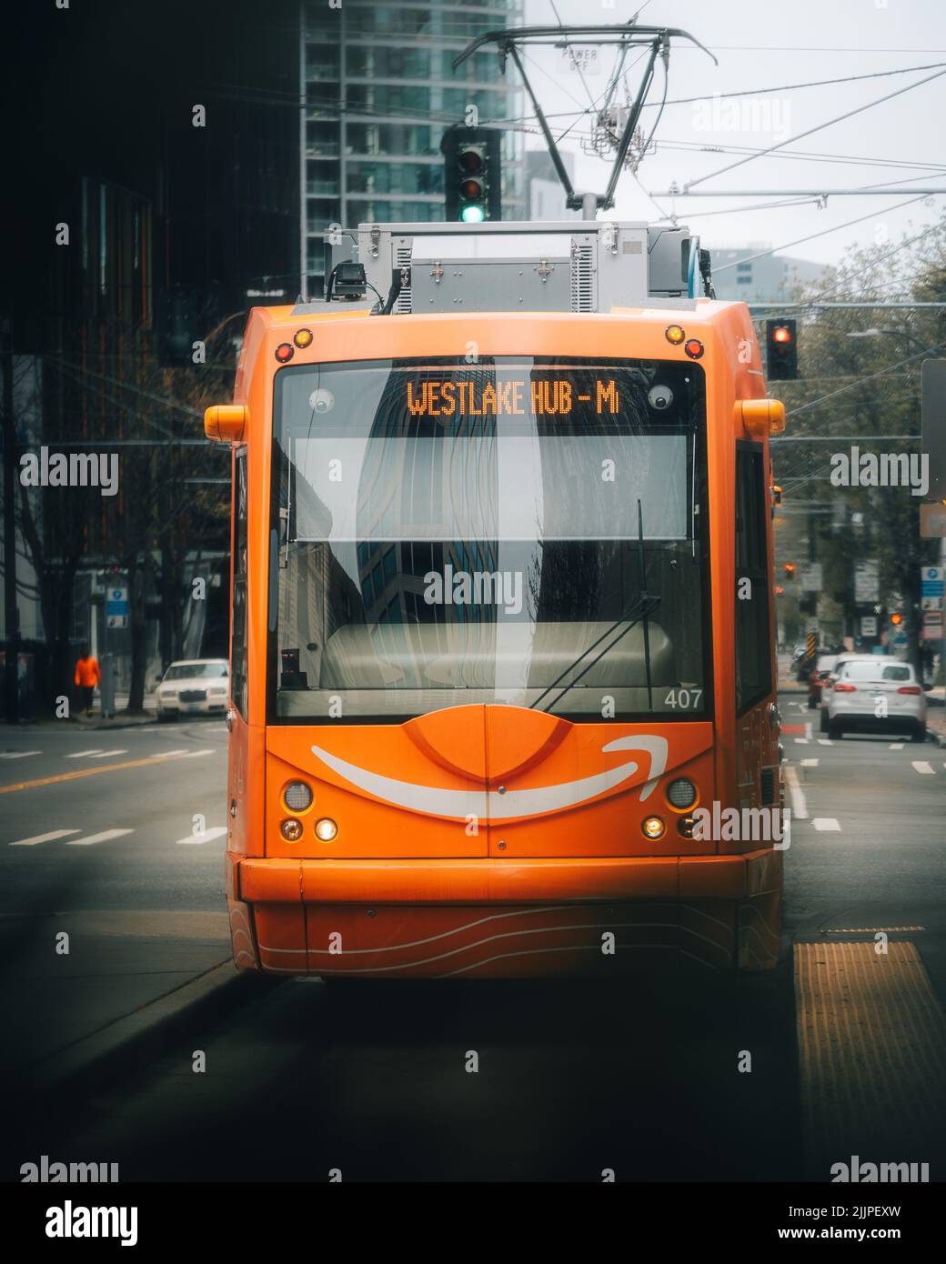 A front view of an orange tram riding down a street Stock Photo - Alamy