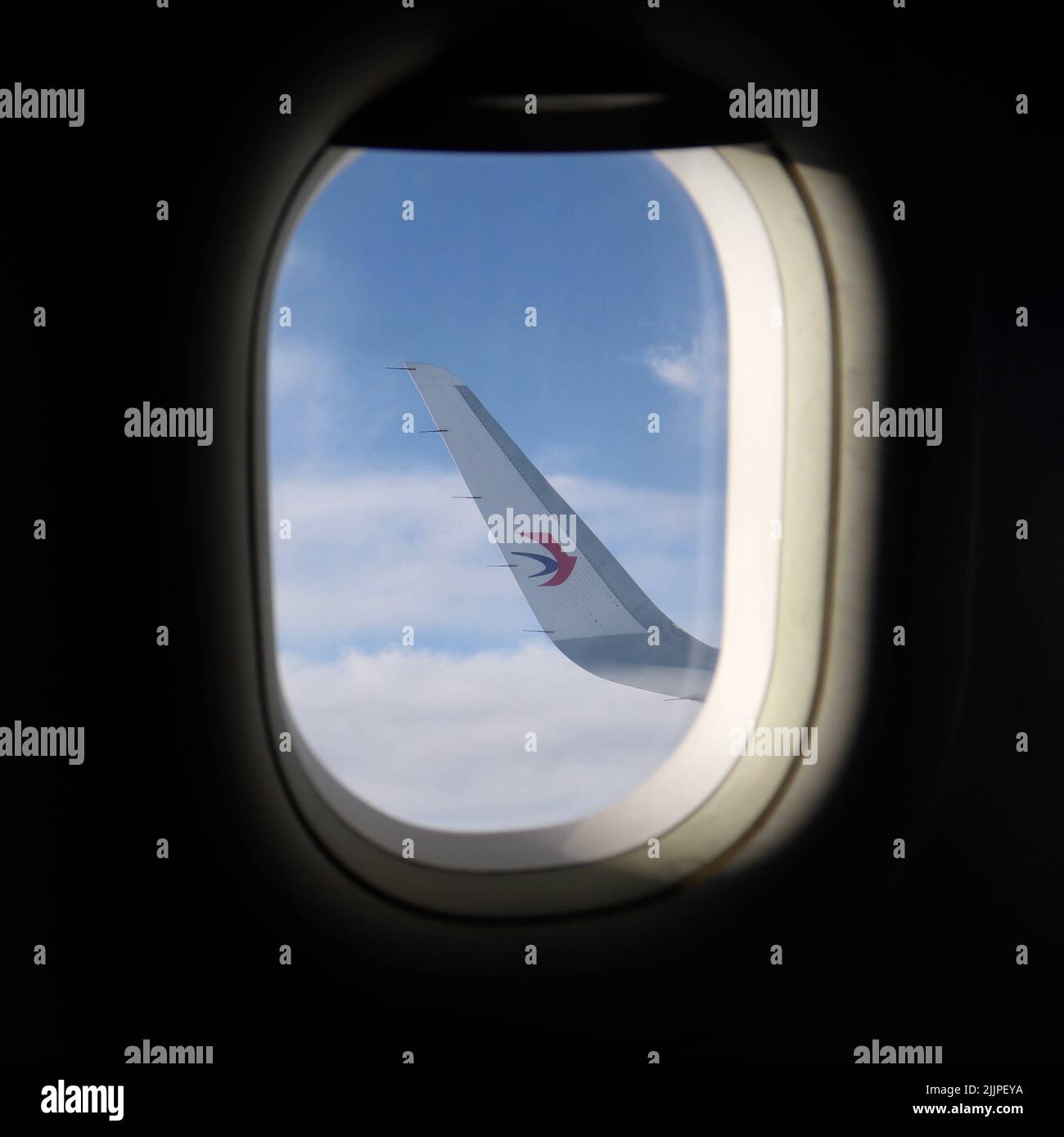 A Side shot of a China Eastern plane wing with clouds in the background ...