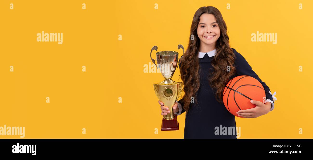 cheerful kid hold basketball ball and champion cup on yellow background ...