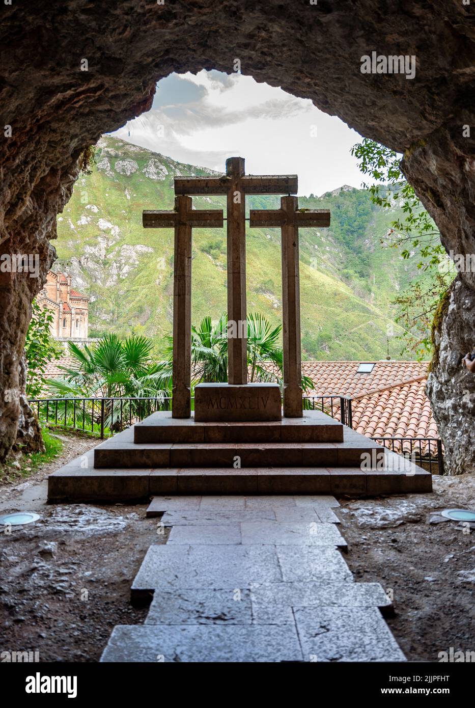 A statue of crosses outside of a church with mountains in the back ...