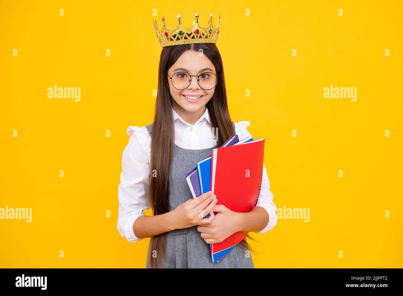 Schoolgirl in school uniform and crown celebrating victory on yellow ...