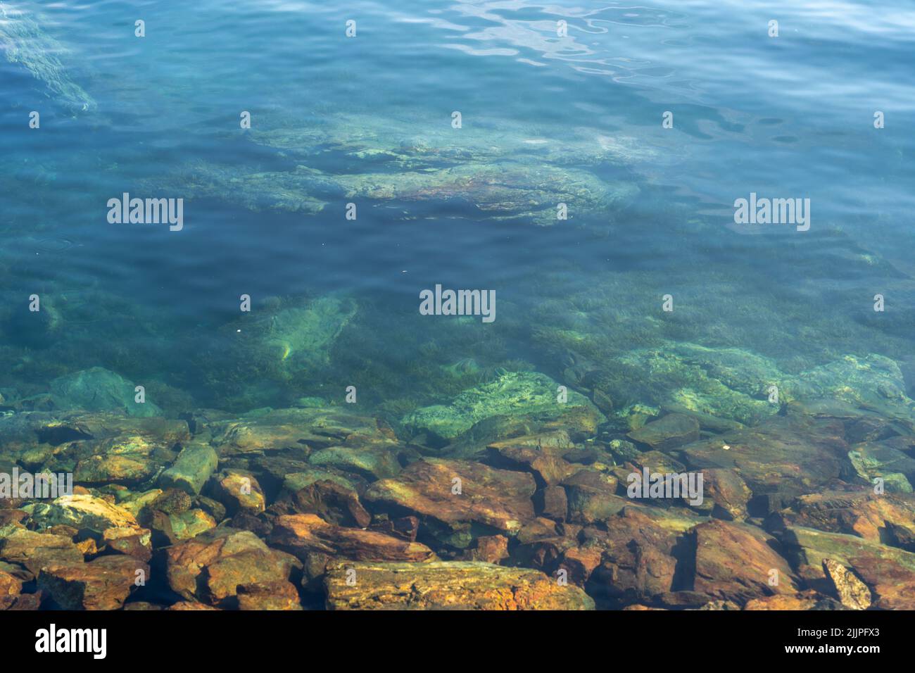 A beautiful view of water with stones underneath Stock Photo - Alamy