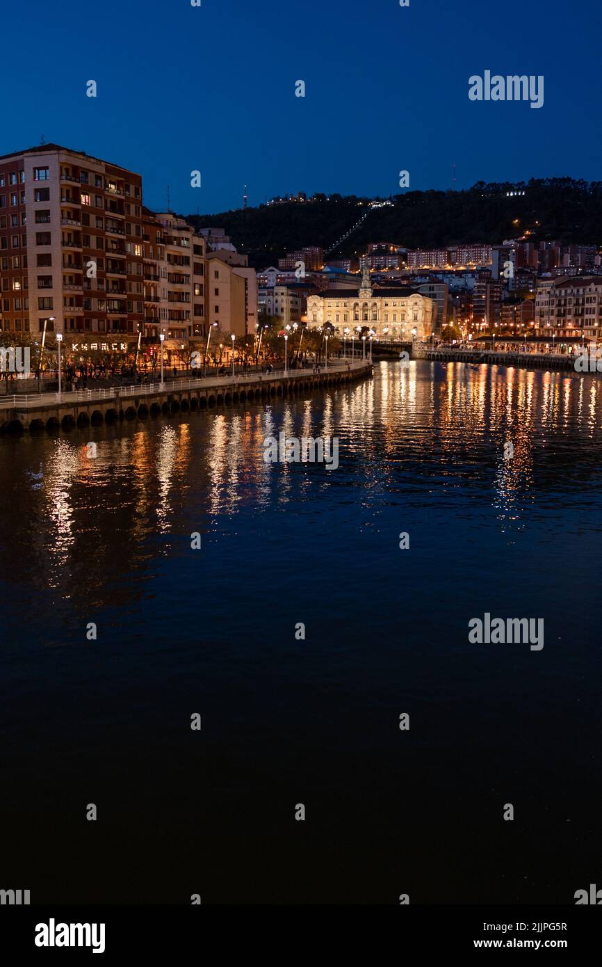 The river water reflecting the coastal buildings in the city of Bilbao ...