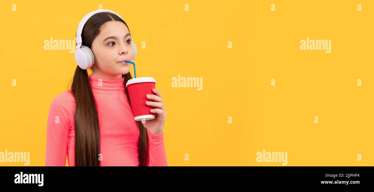 serious child listen music in headphones drink from paper cup on yellow ...
