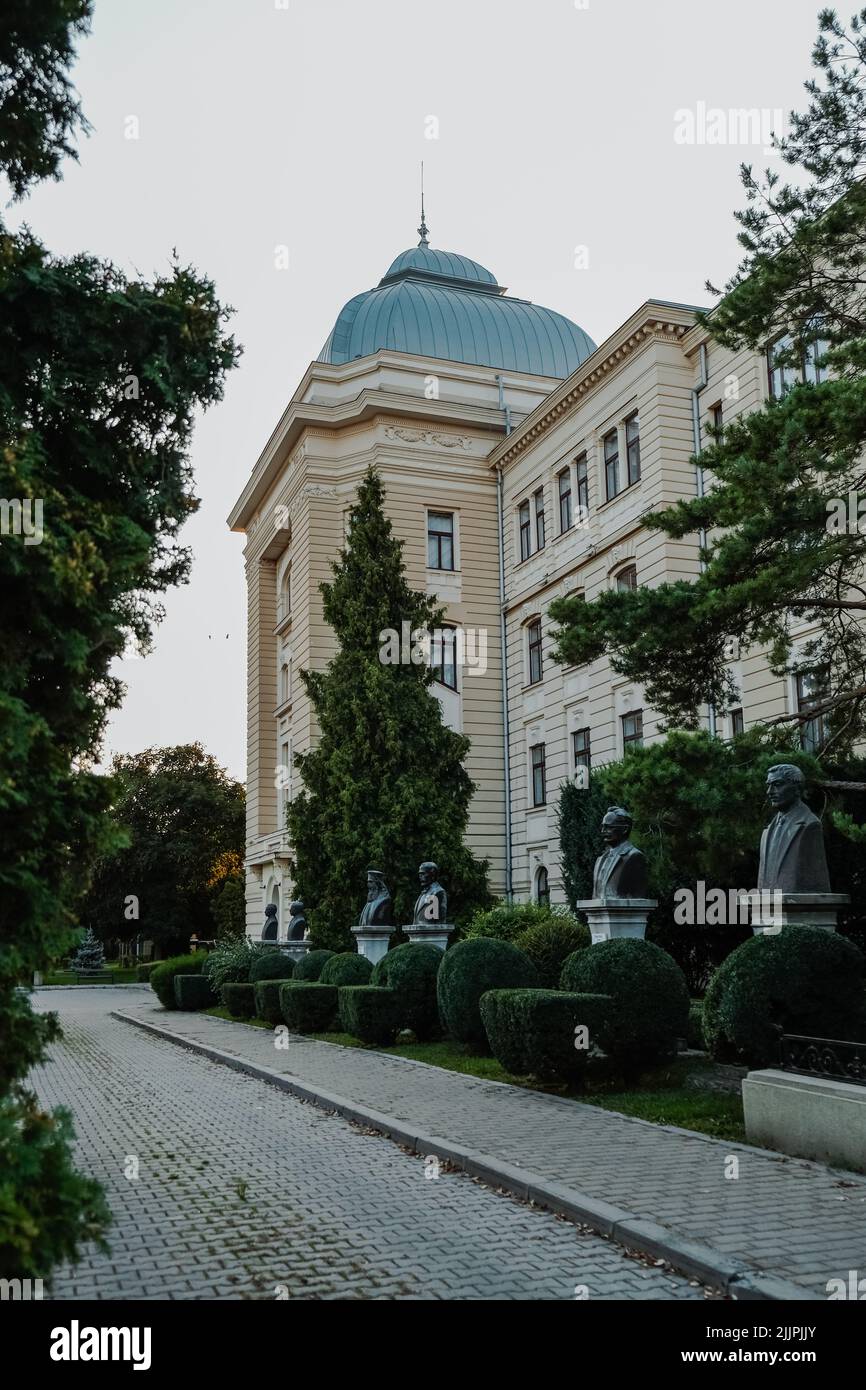 A vertical shot of a front yard of a building with a line of sculptures ...