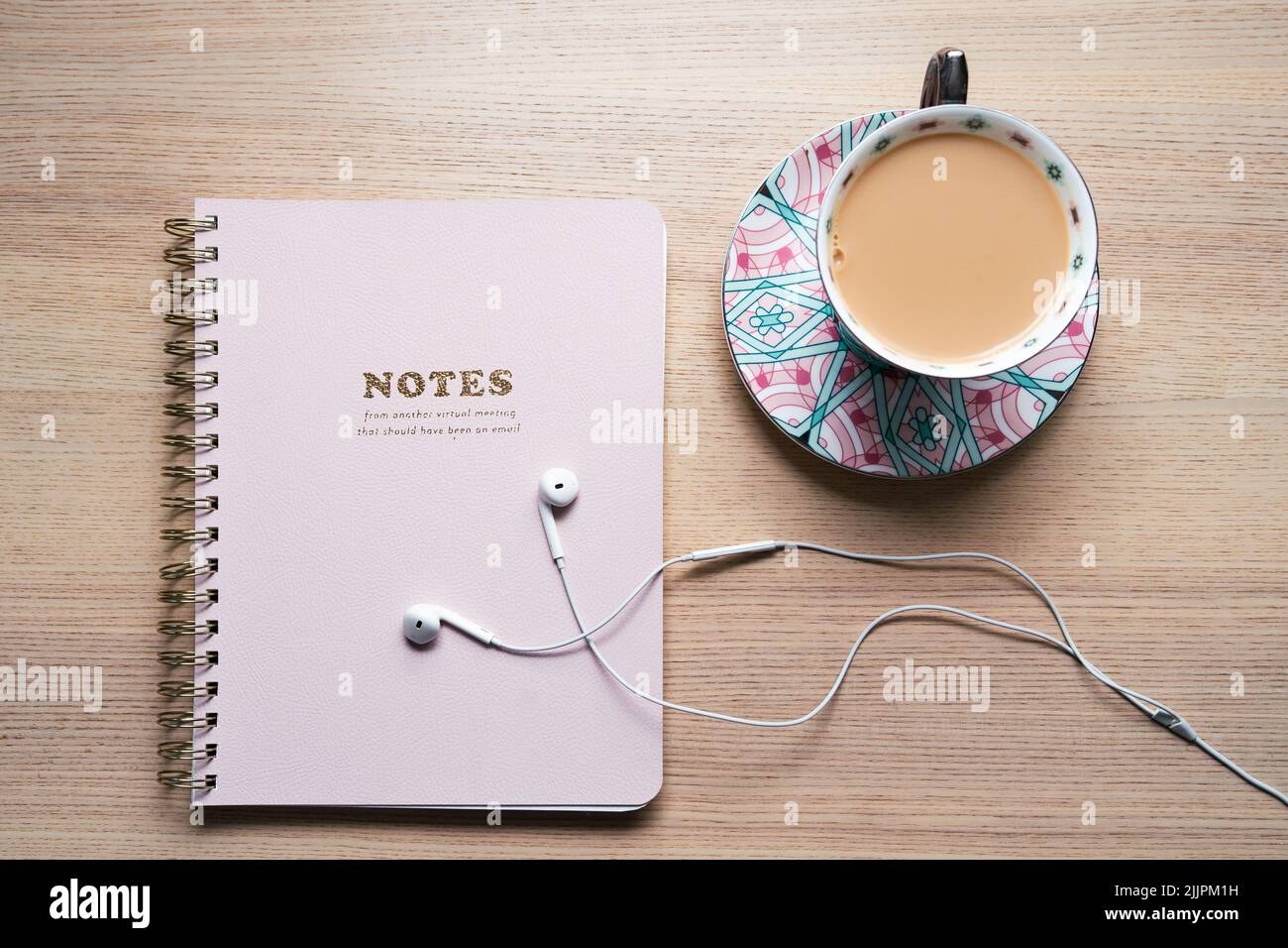 Notebook lying on the table with white headphones and a cup of tea in a ...