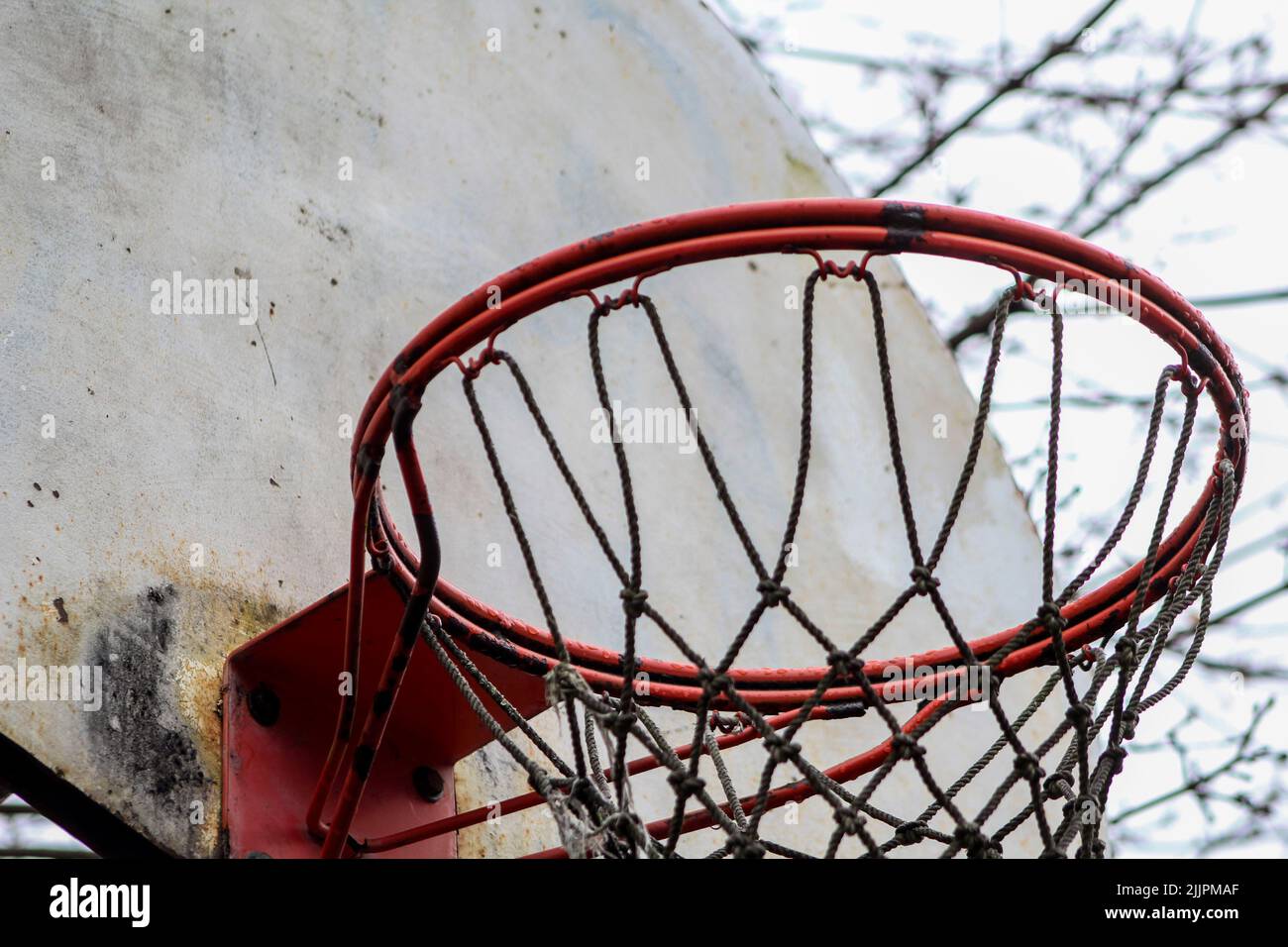 A closeup of a red metal basketball hoop in a playground hanging from a ...