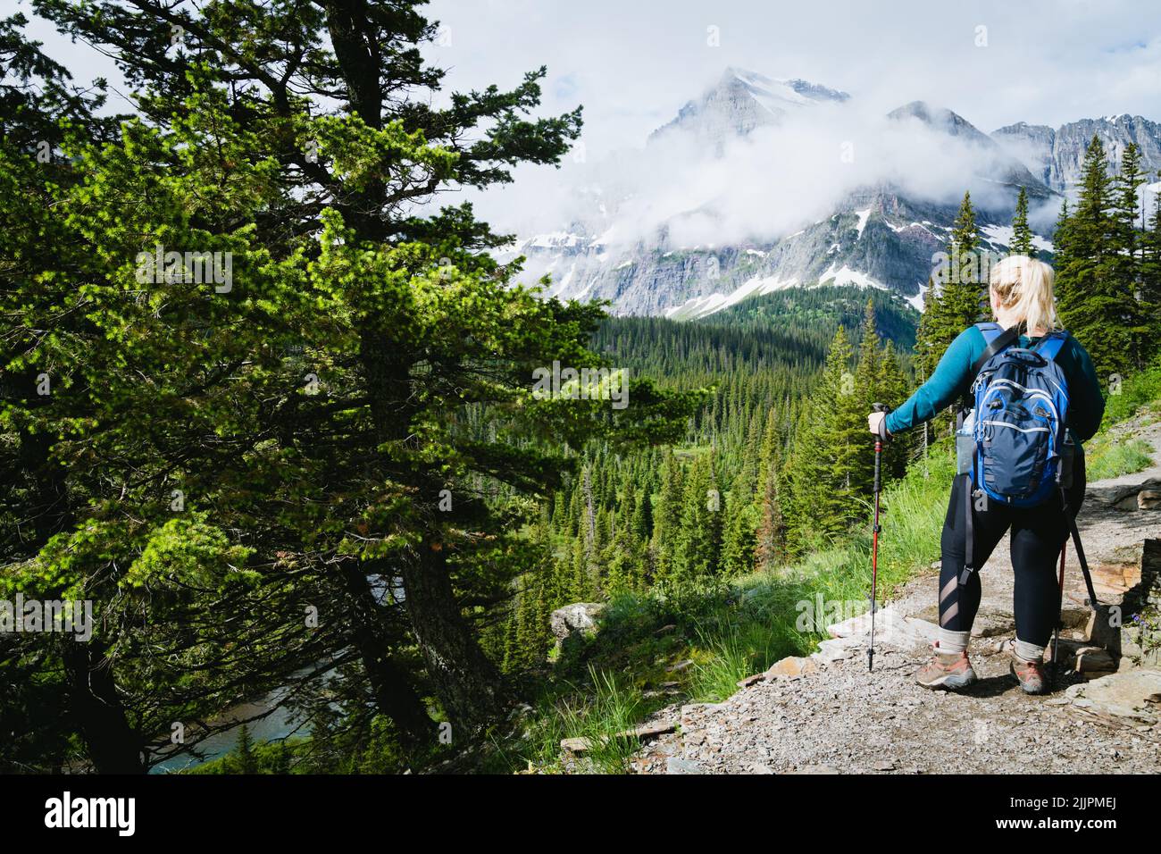 Blonde woman hiker takes a moment to enjoy the scenery along the ...
