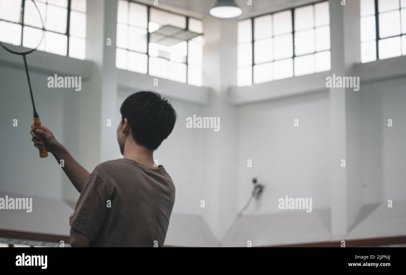 A back view of a young male playing badminton on an indoor court Stock ...