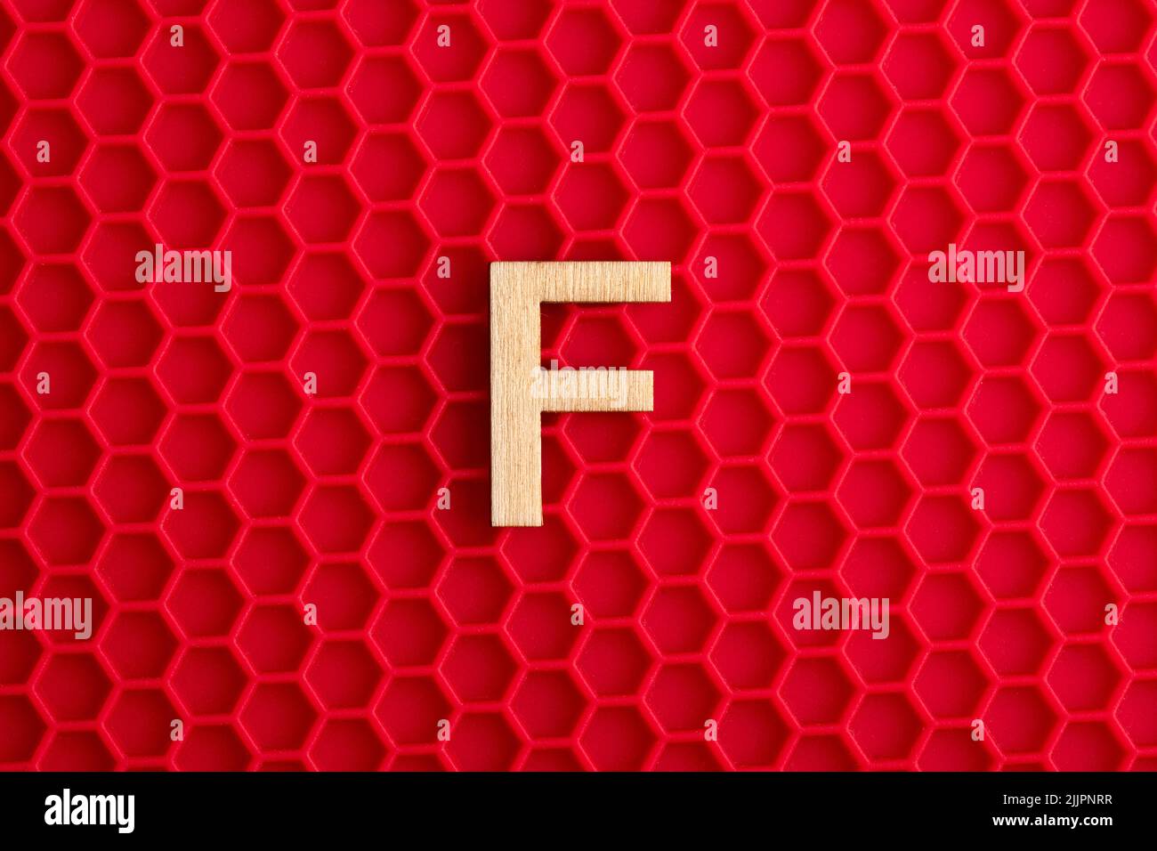 Capital letter F - White piece on silicone background with red hexagons ...