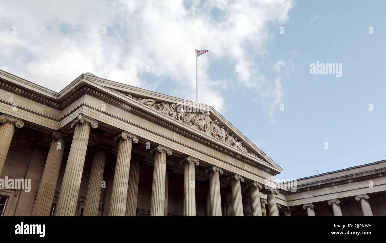 A low angle shot of the British Museum In London, Uk, with waving flag ...