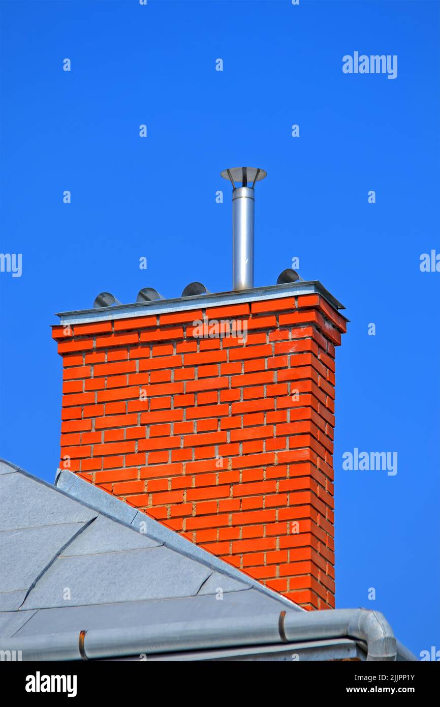 orange chimney brick pipe on the roof on blue sky in sunny day, modern ...