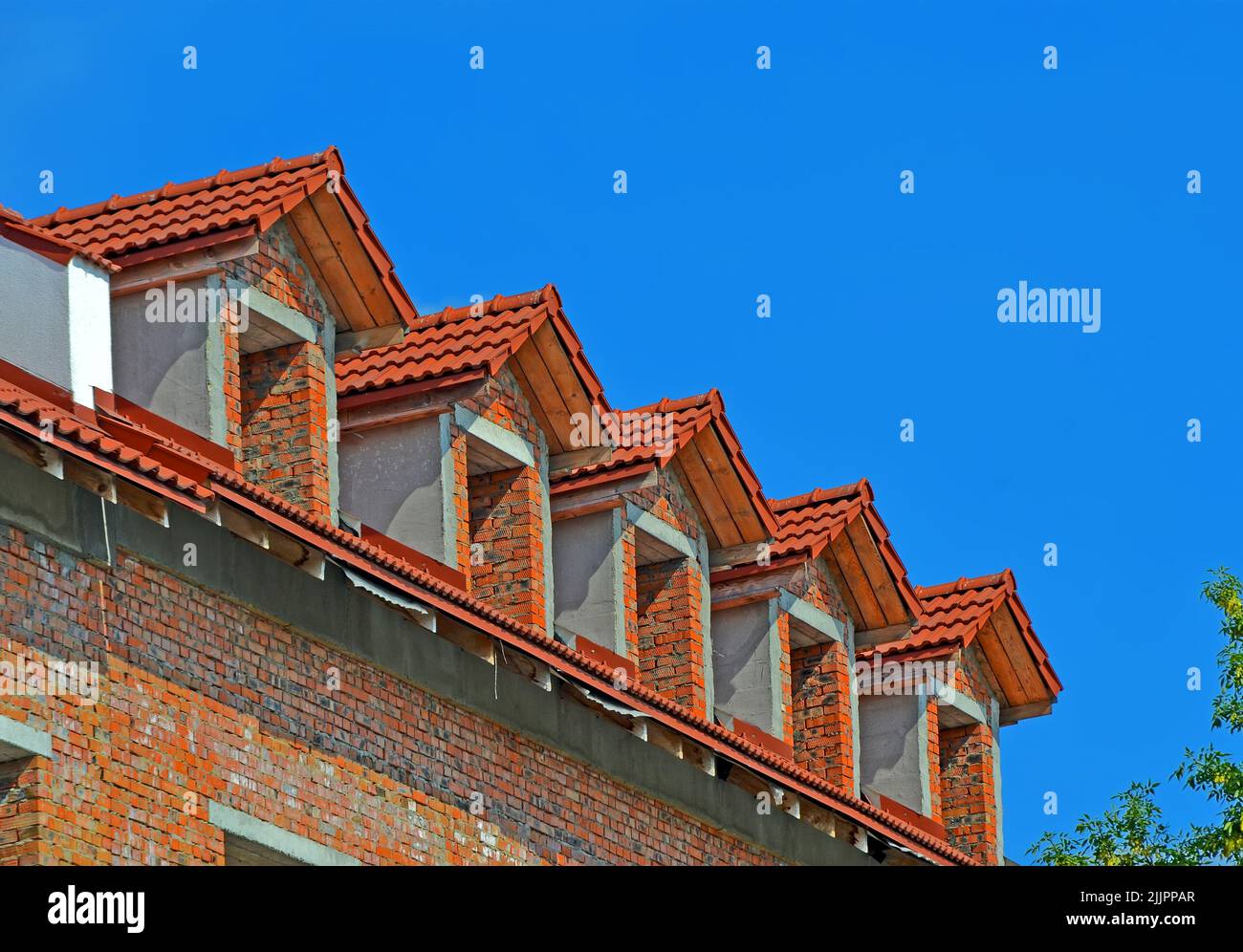 red brick tile roof with triangle windows line on blue sky in sunny day ...