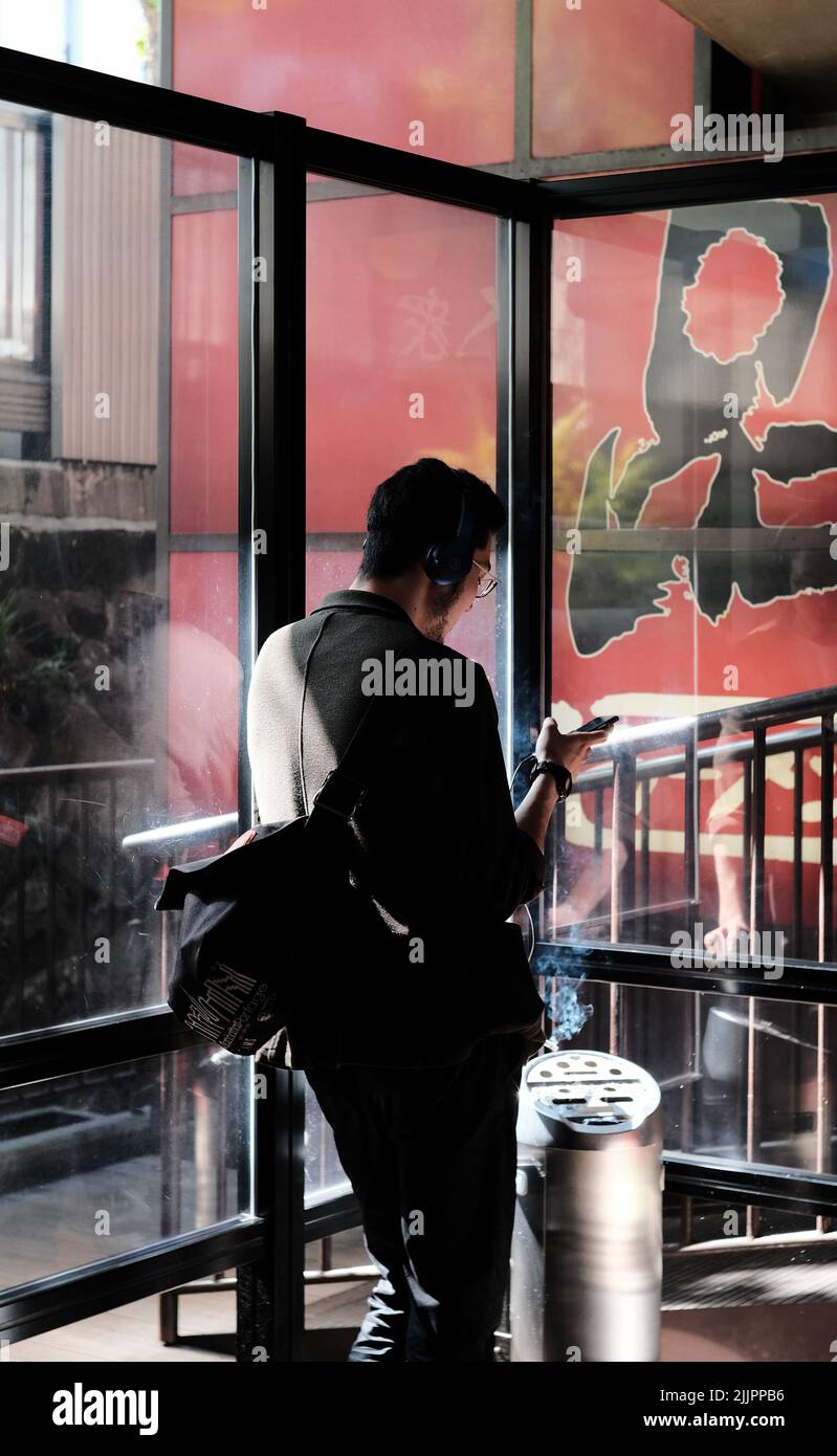 A vertical shot of a man smoking inside a mall room in Shinagawa, Tokyo ...