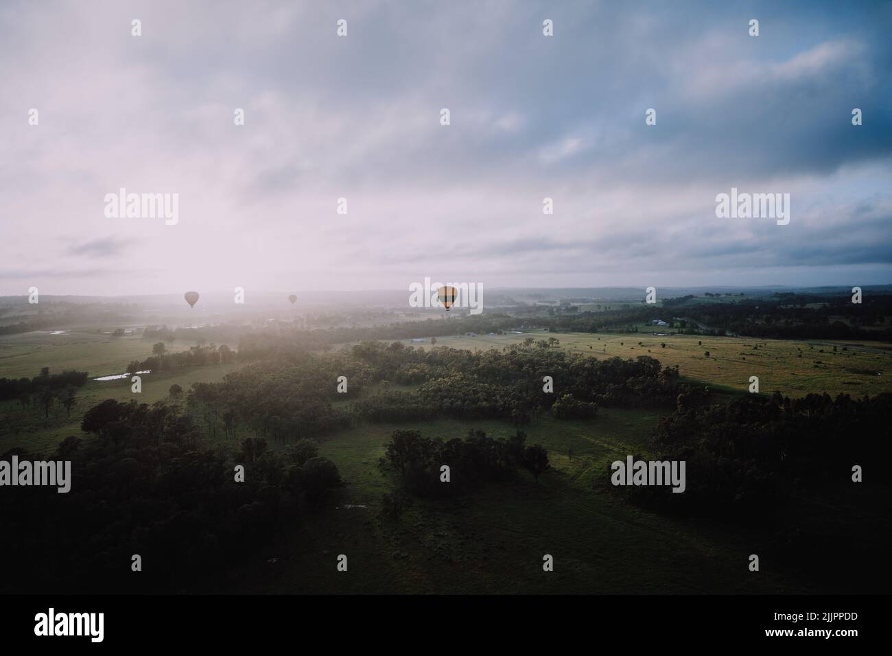 An aerial shot of balloons in the air over a valley in the sunrise ...