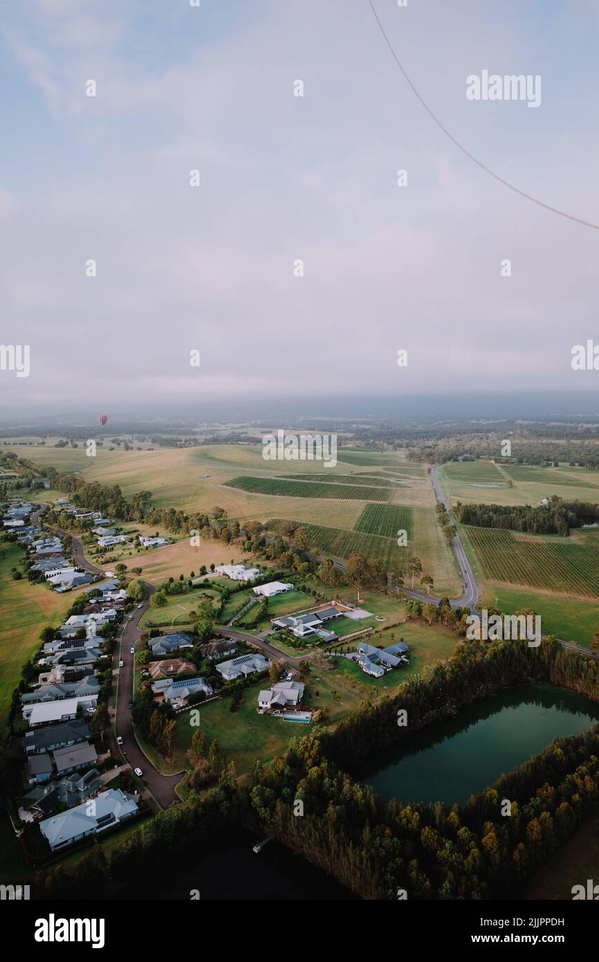 A vertical aerial shot of buildings in a valley next to agricultural ...