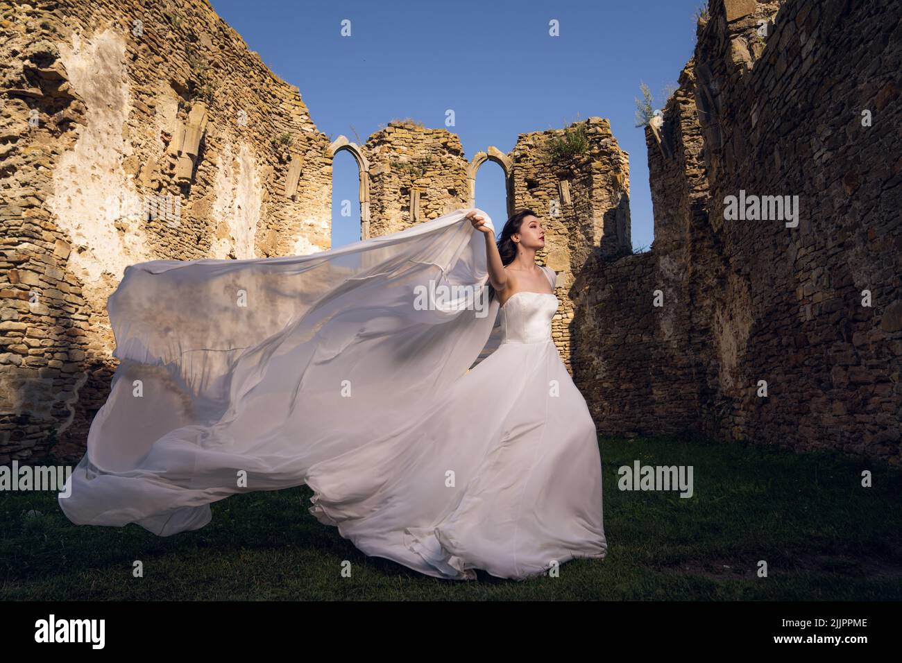 A beautiful shot of a Caucasian female in an elegant white dress posing ...