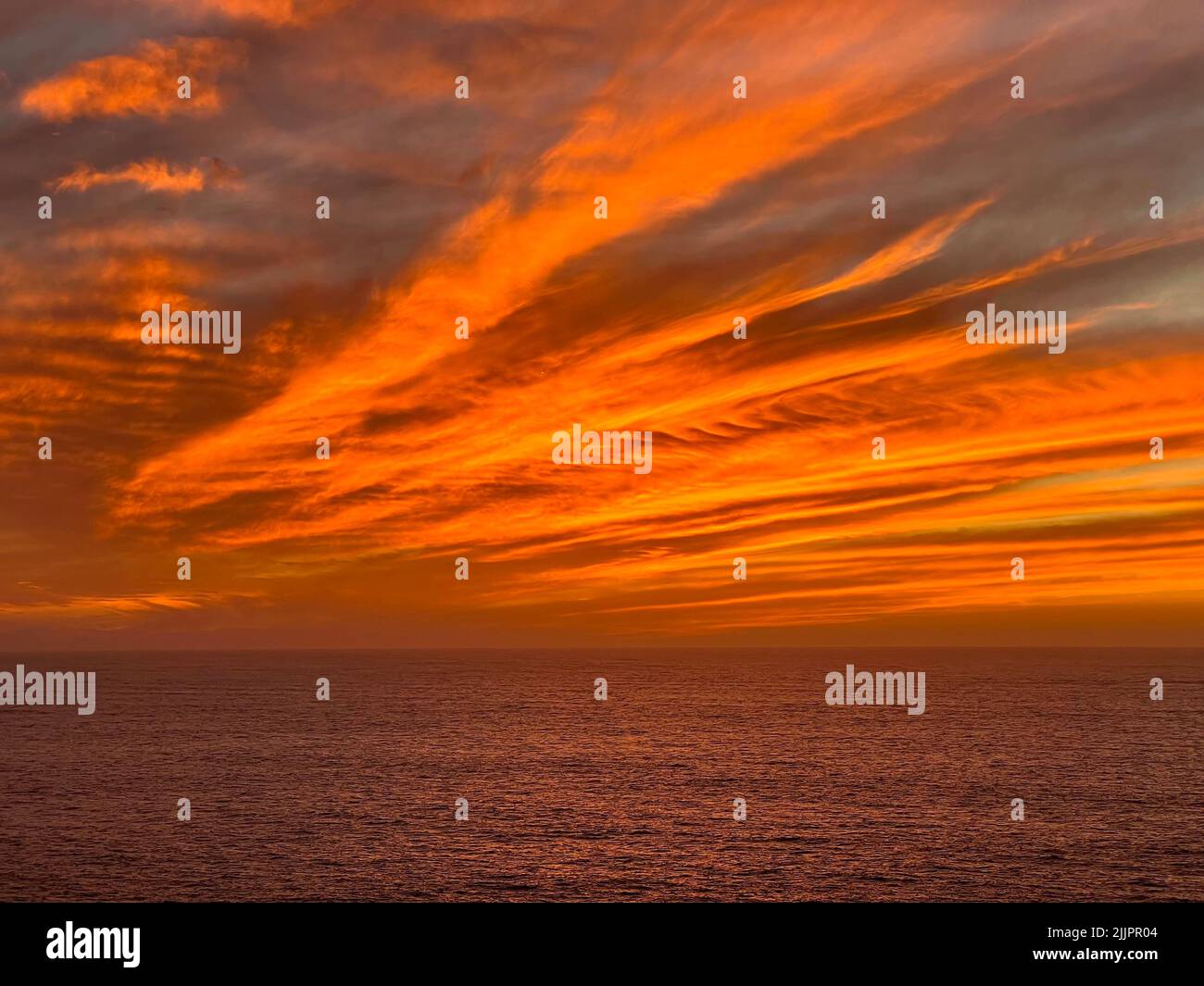 A mesmerizing orange cloudy sunset sky over a tranquil sea Stock Photo ...