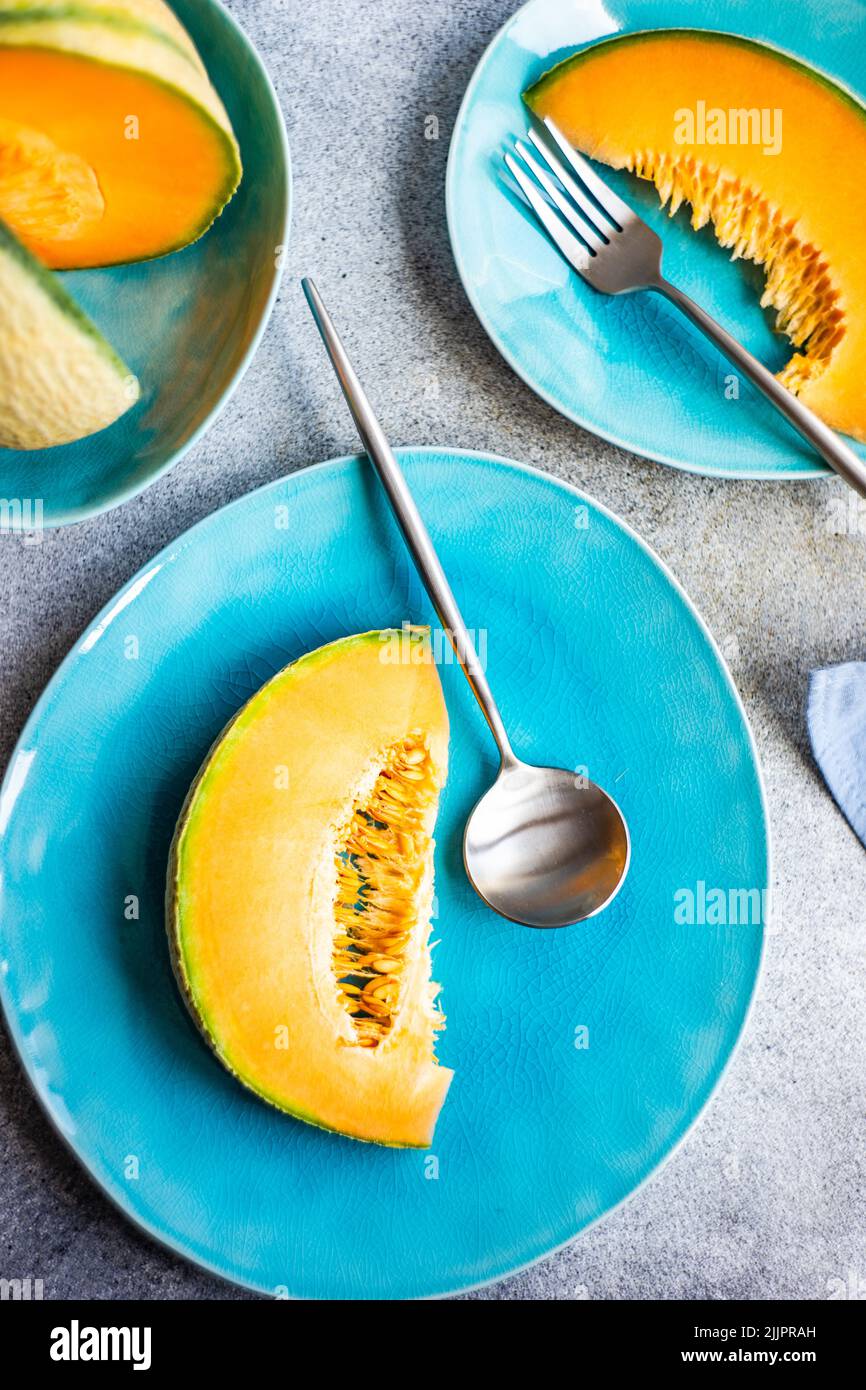Overhead view of cantaloupe melons and slices of melon on plates Stock ...